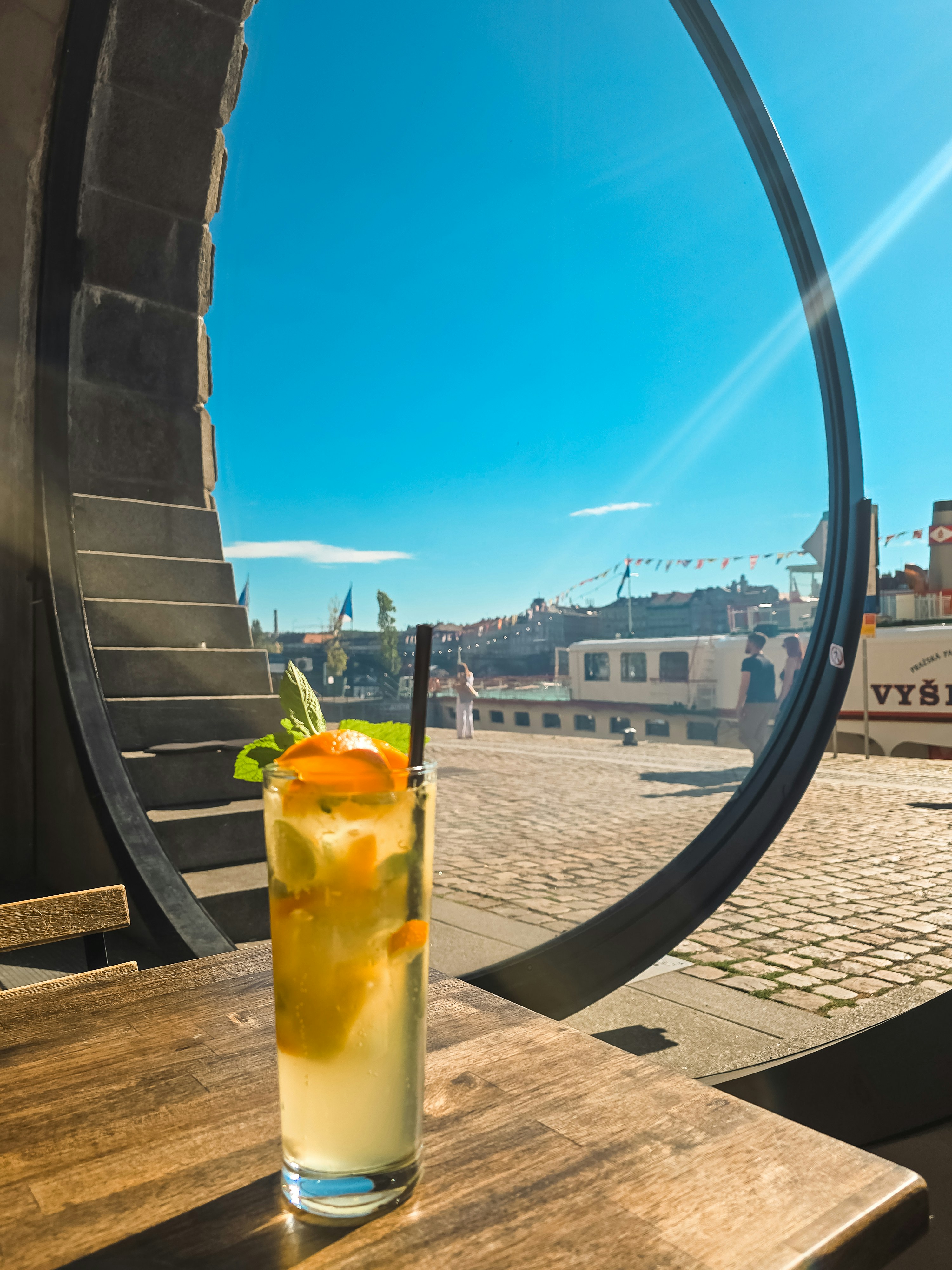 Citrus Spritzer on Circular View: Sunlit Terrace Through a Ring Window
