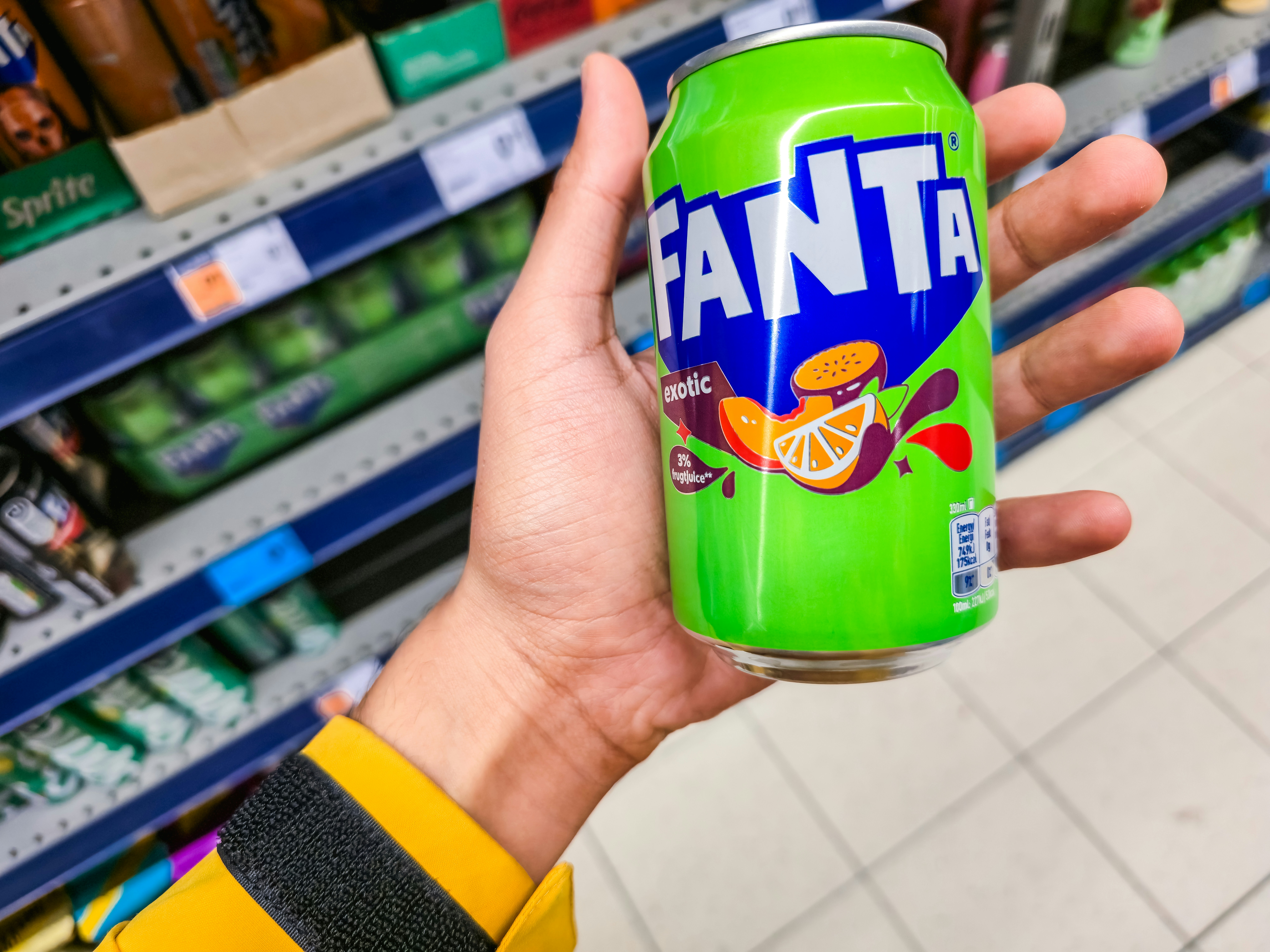 Green Fanta in Hand Over Aisle: A Pop of Citrus on the Shelf