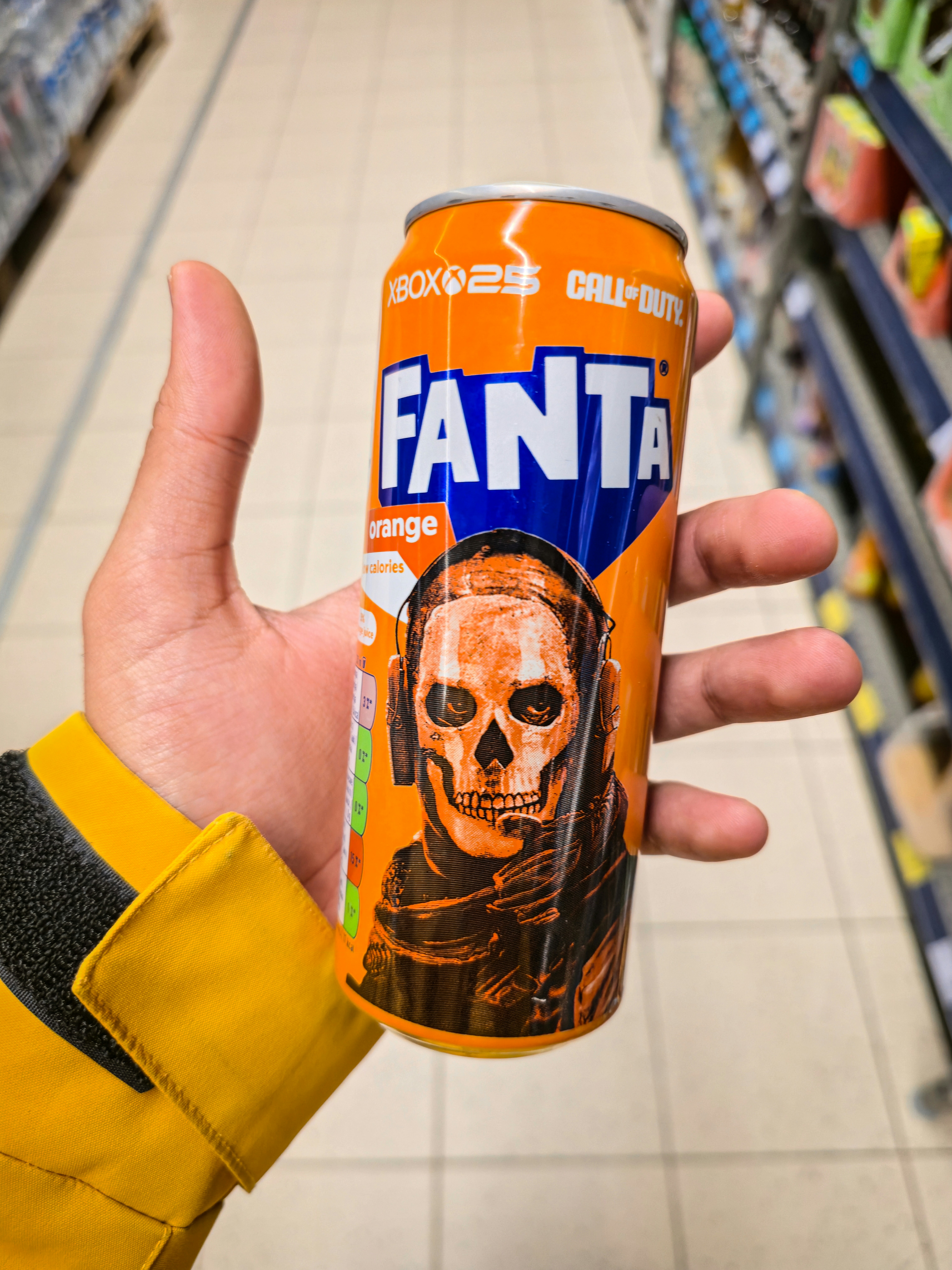 Orange Fanta Can Gripped in Hand Inside Aisle