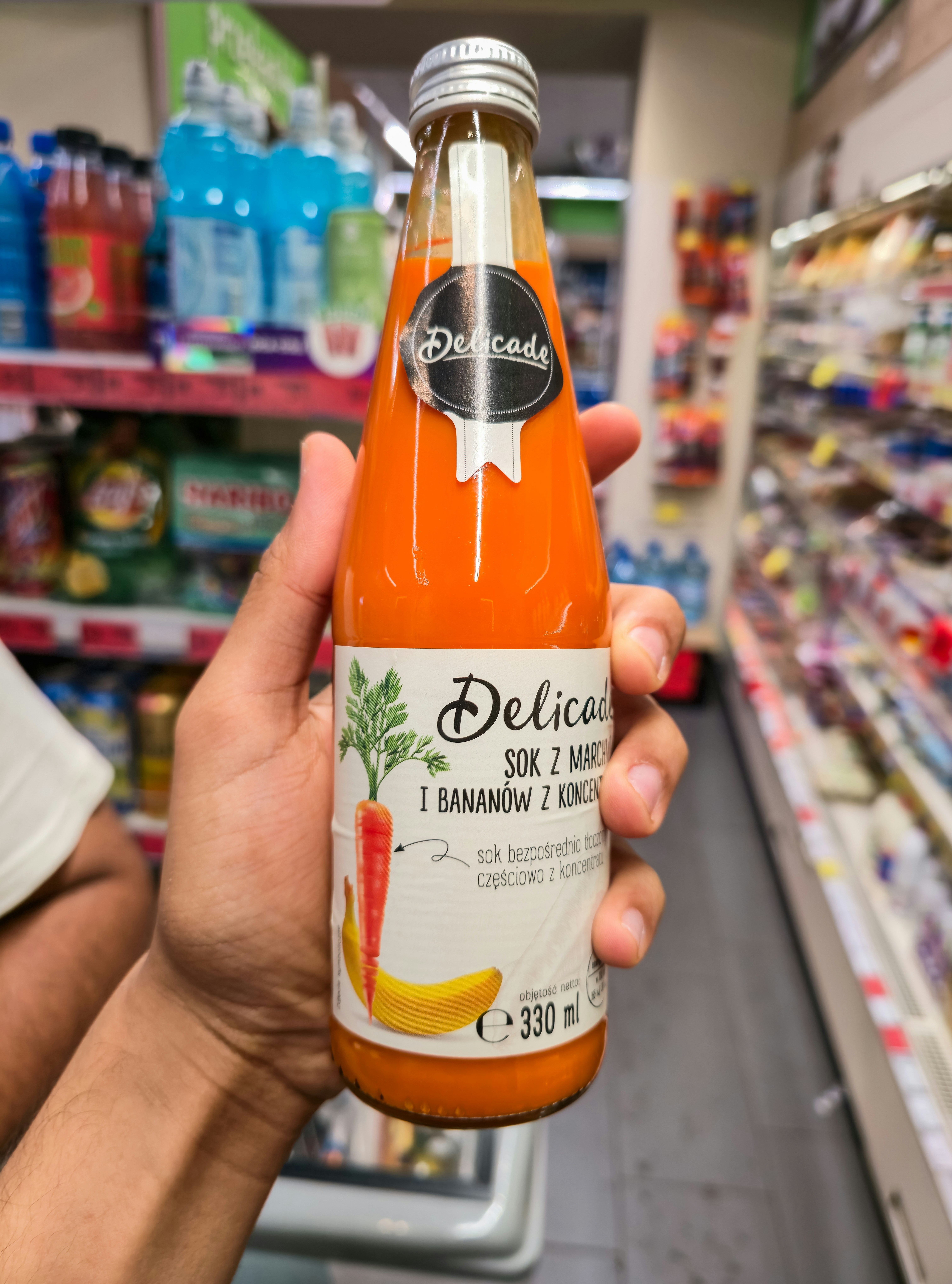 Orange Elixir in Focus: A Handheld Bottle Gripped in a Aisle