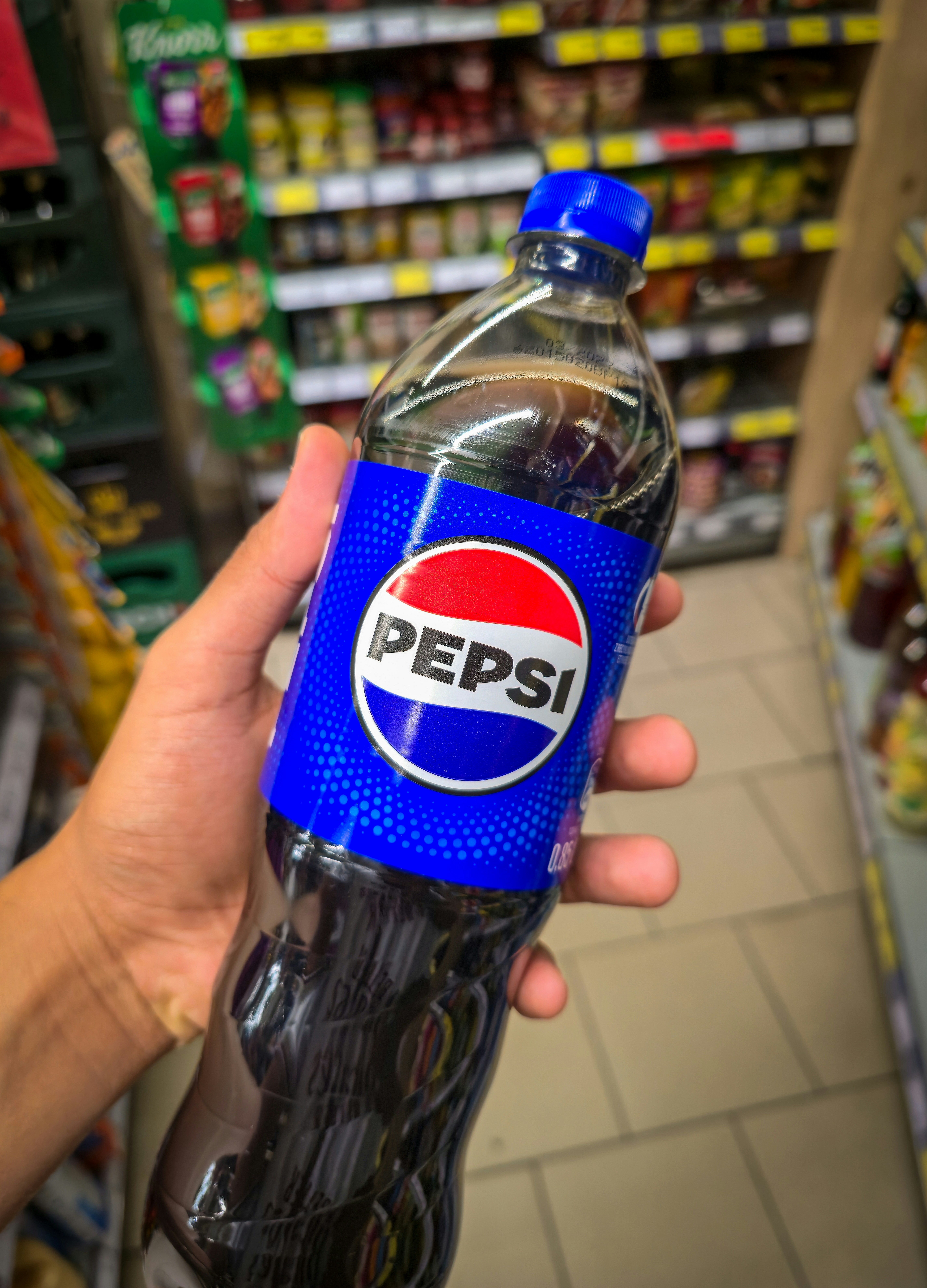 Pepsi Bottle Grasp: Bold Label in a Grocery Aisle