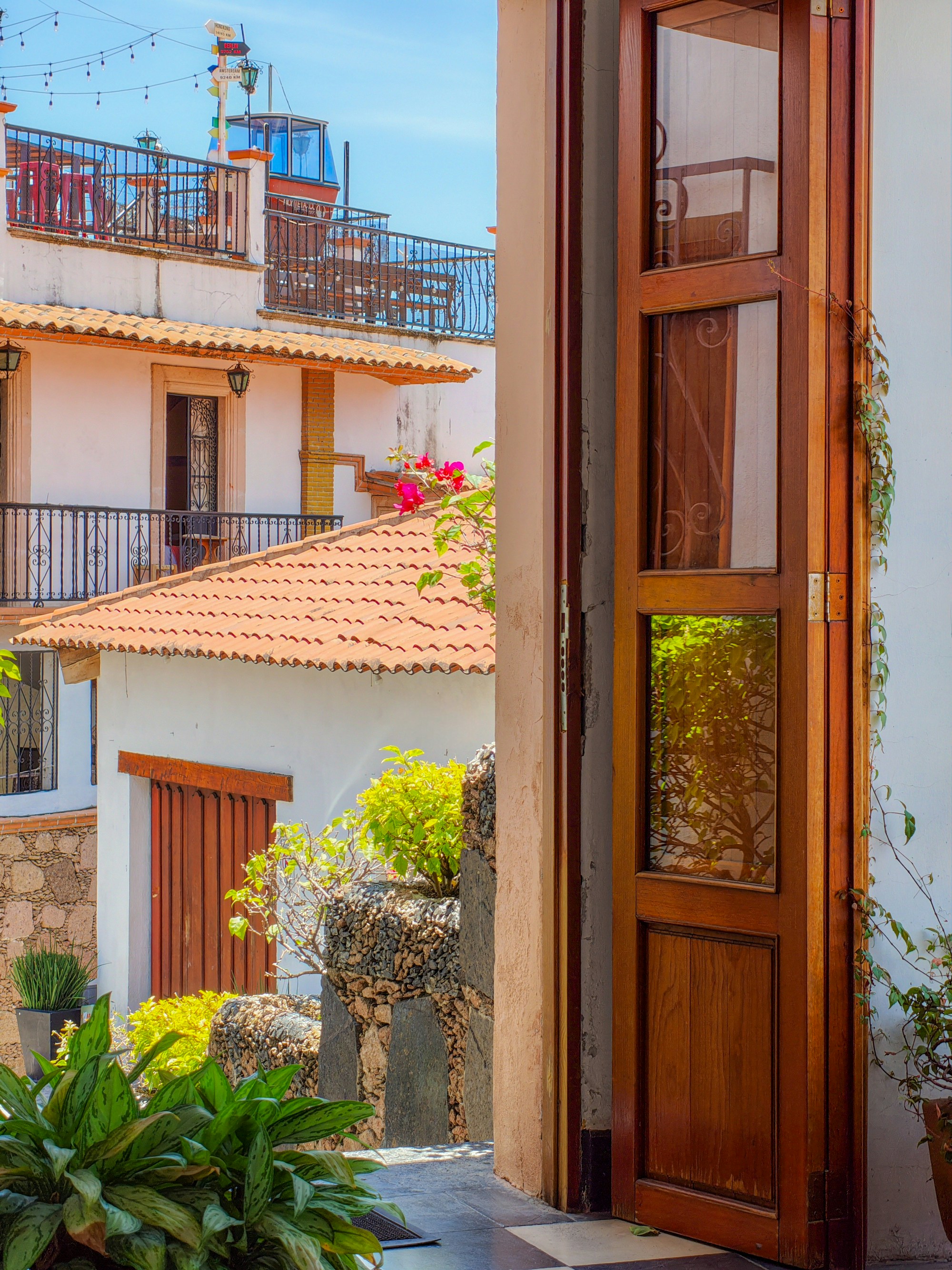 A wooden door opening to a view of white buildings with terracotta roofs