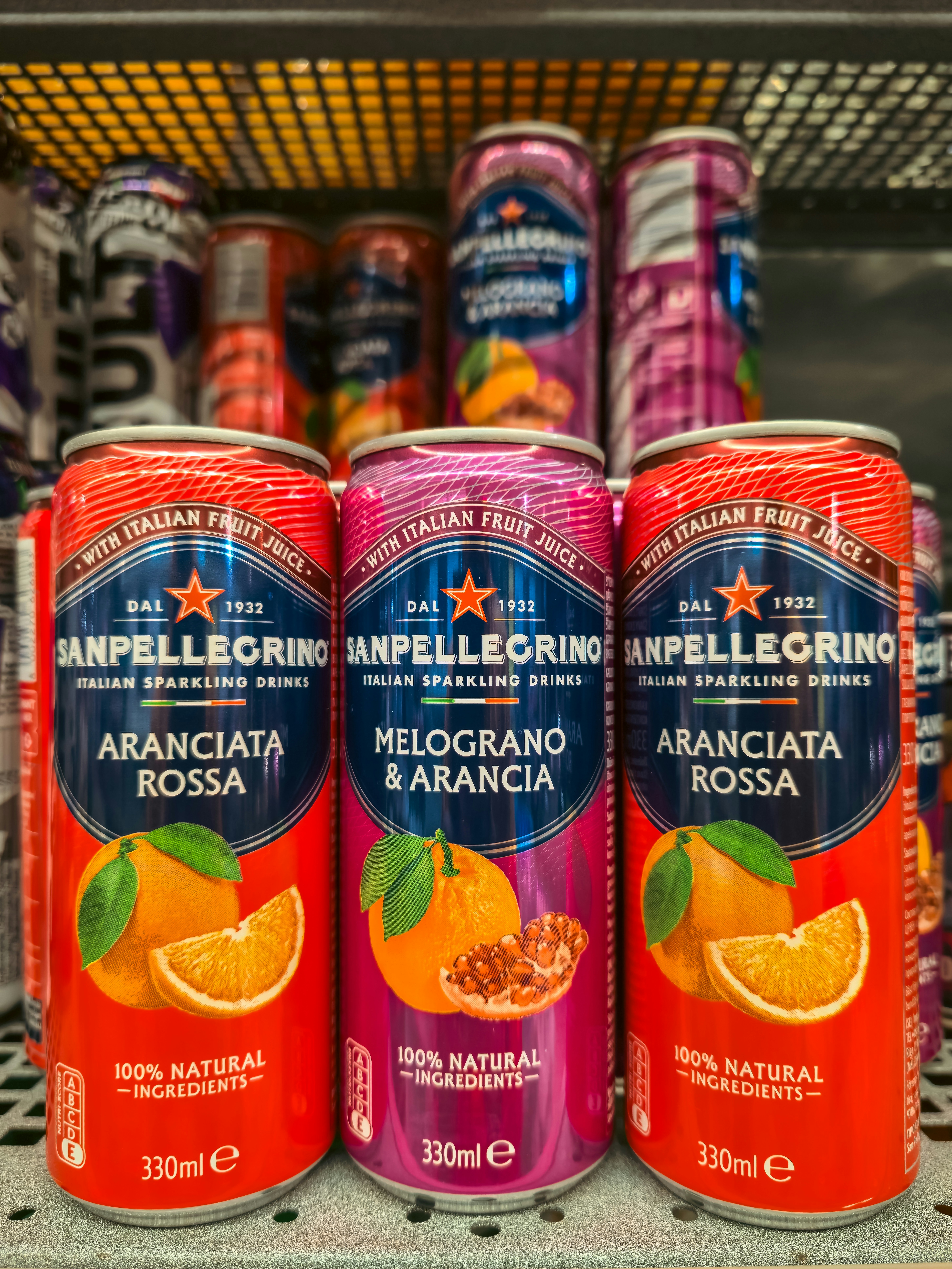Vibrant trio: Aranciata Rossa cans line up on a shelf