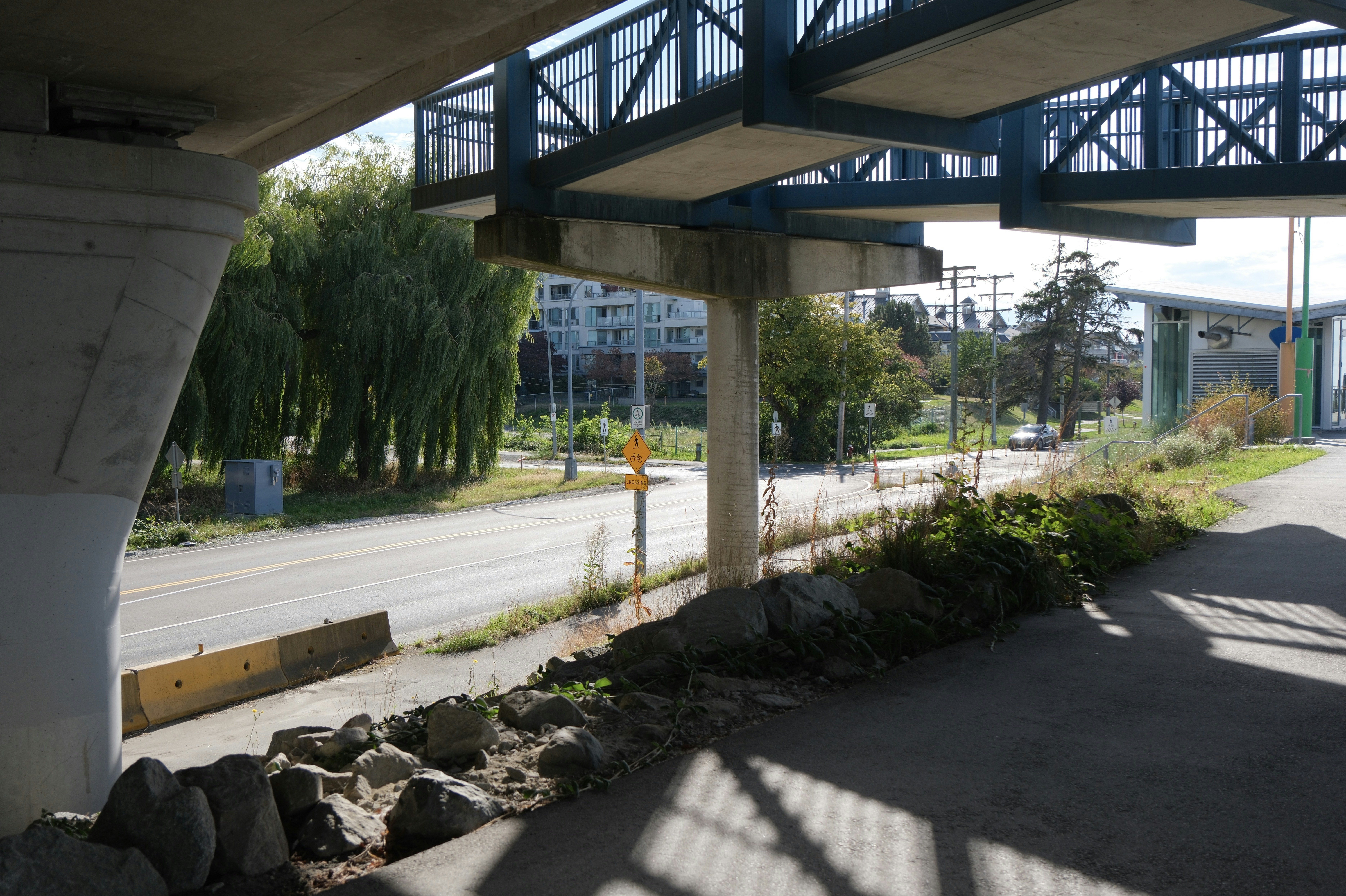 Shadowed Walkway Beneath a Modern Overpass