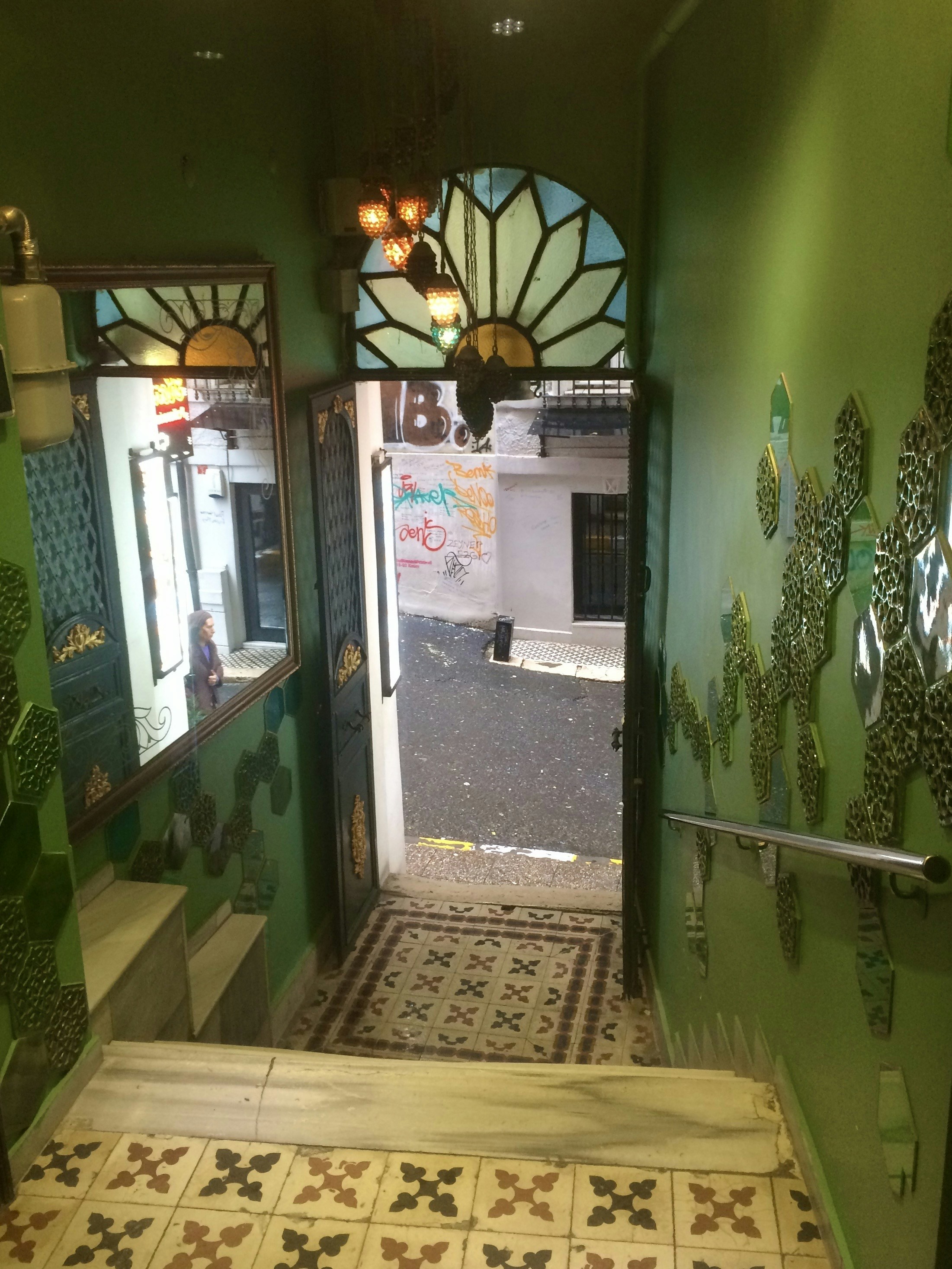 Green staircase to the street: mosaic tiles and stained-glass archway