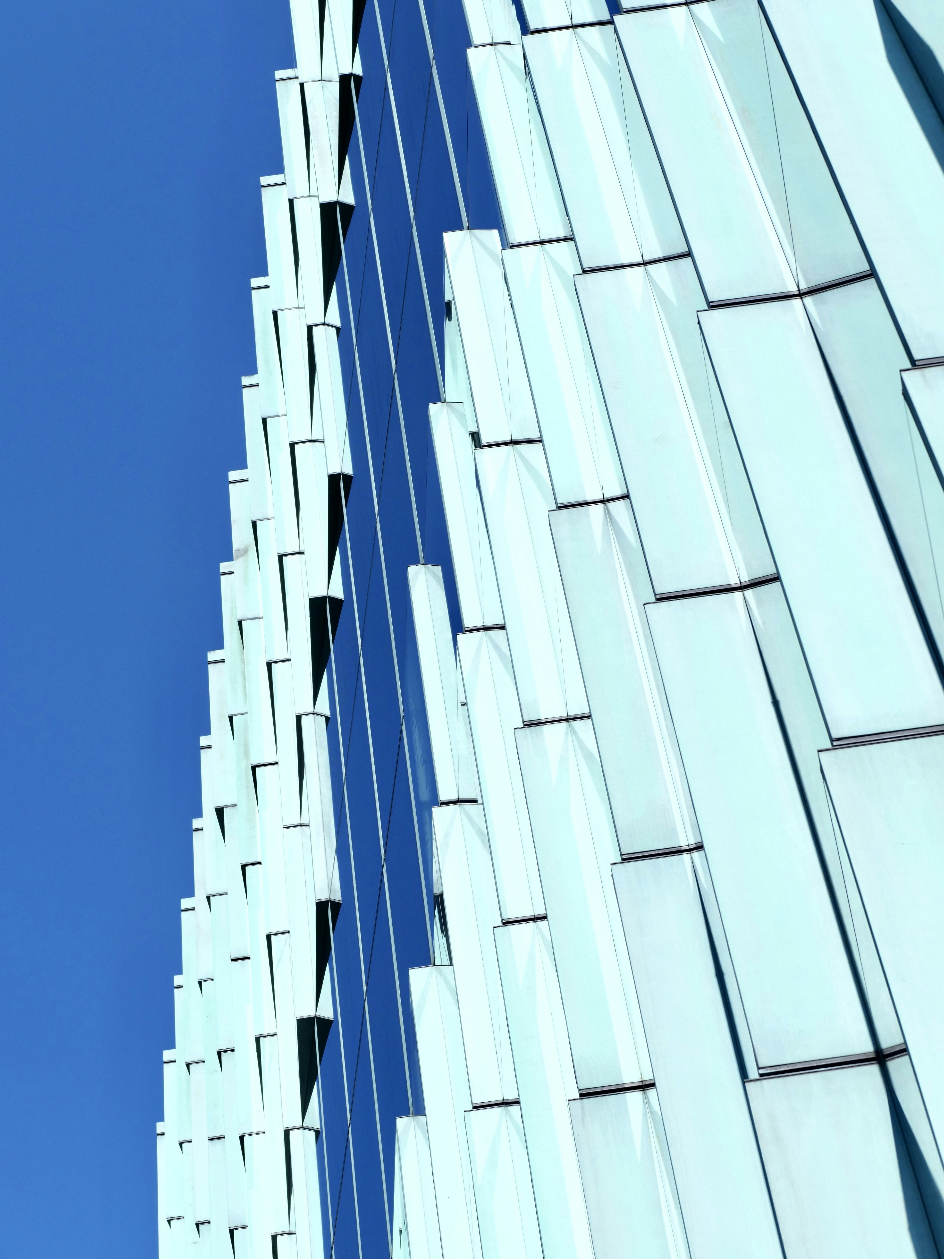 Emerald Facade in Motion: Geometric Glass Steps Against a Clear Blue Sky