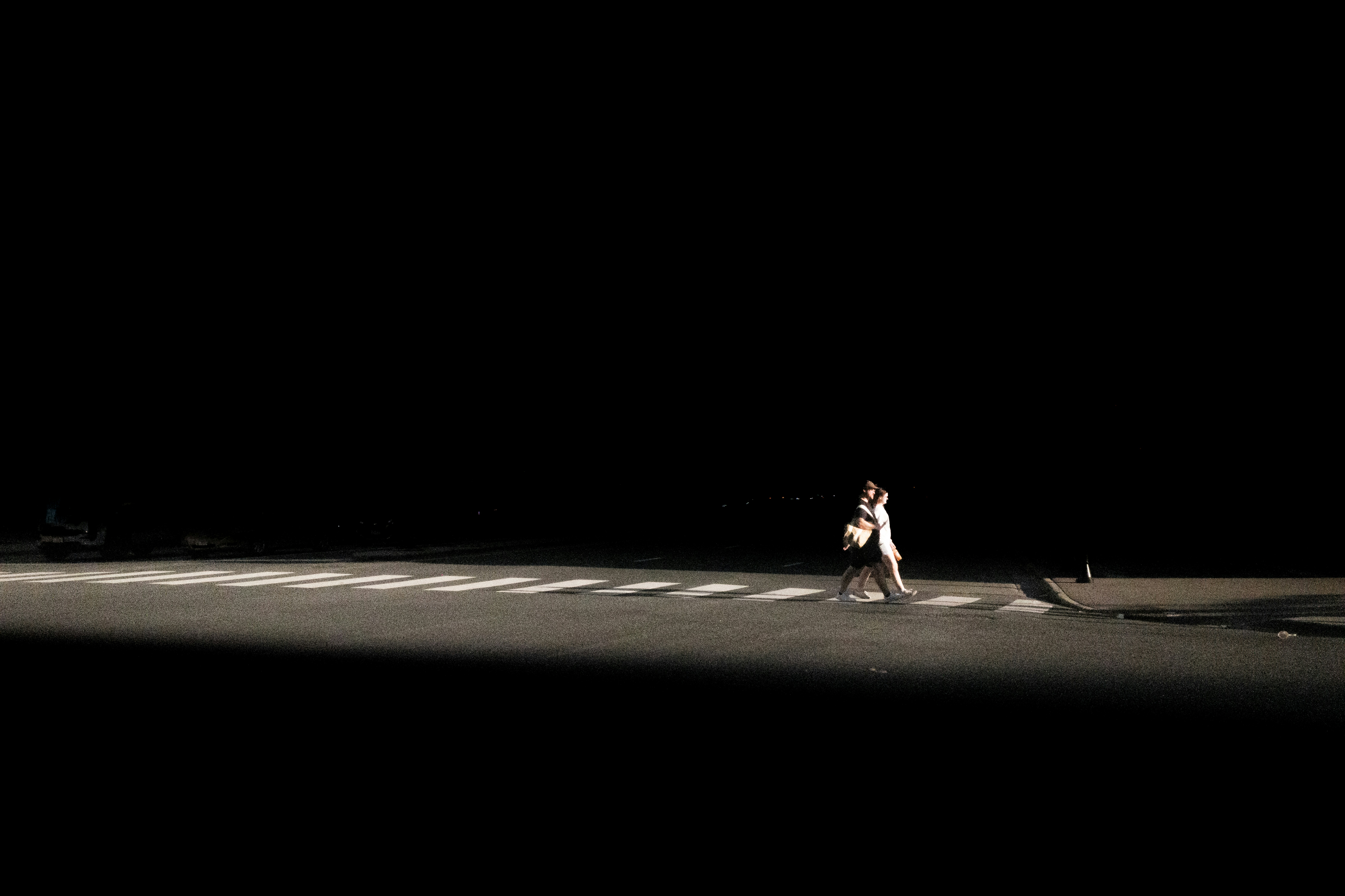 Lone Pedestrian Beneath a Narrow Beam of Streetlight