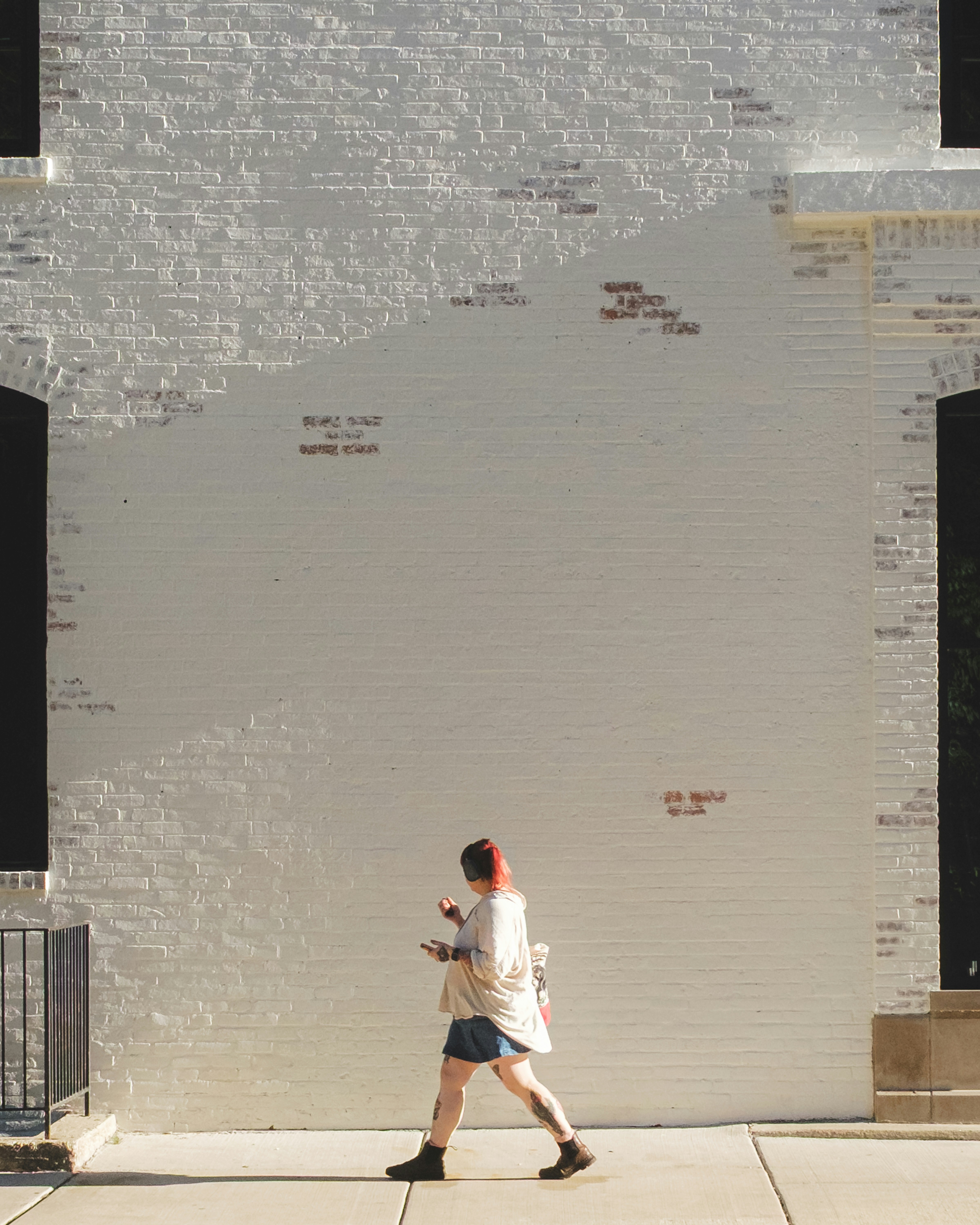 Passing Figure in a Sunlit Brick Wall Corridor