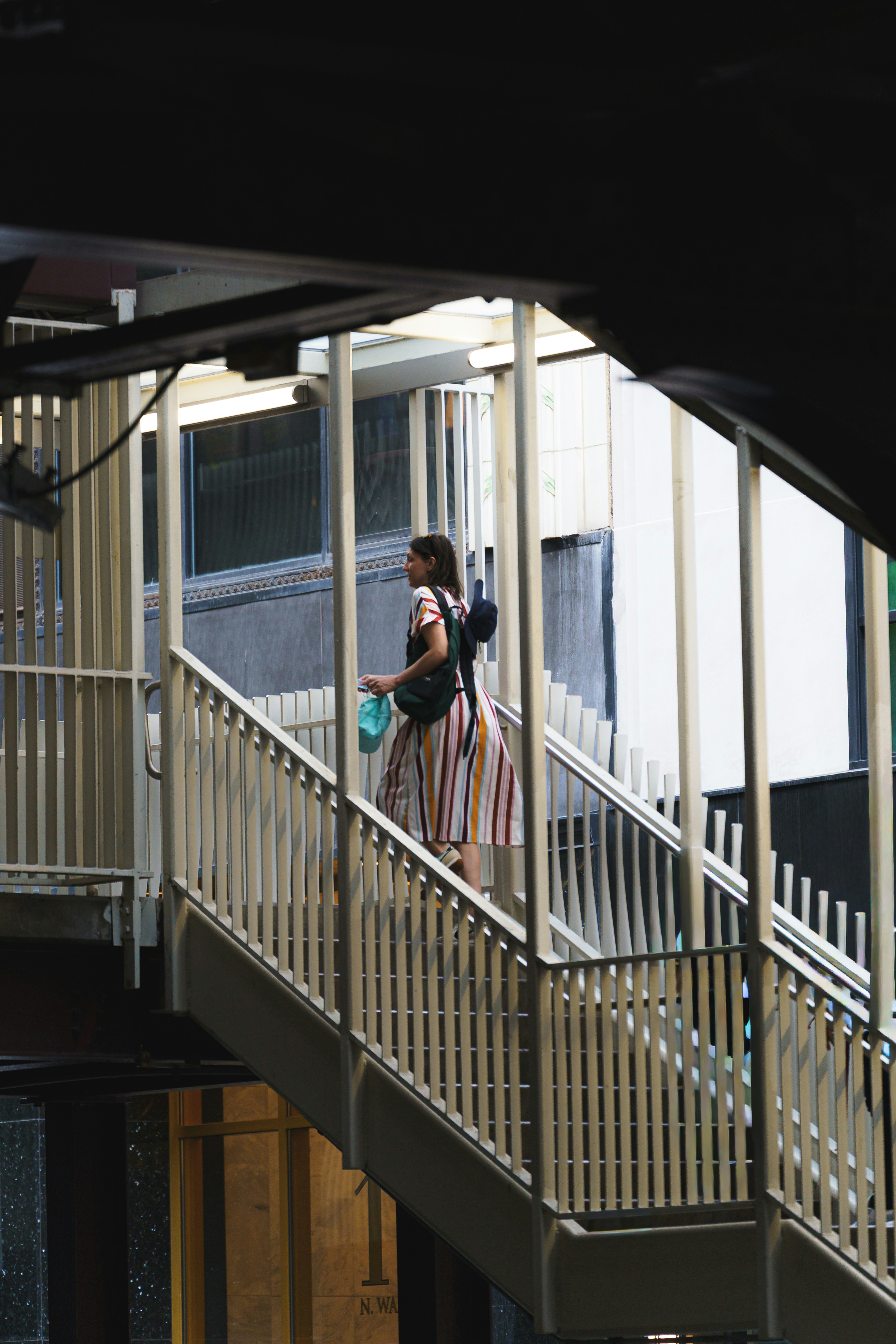 Ascending Light: Woman in Striped Dress on Urban Staircase