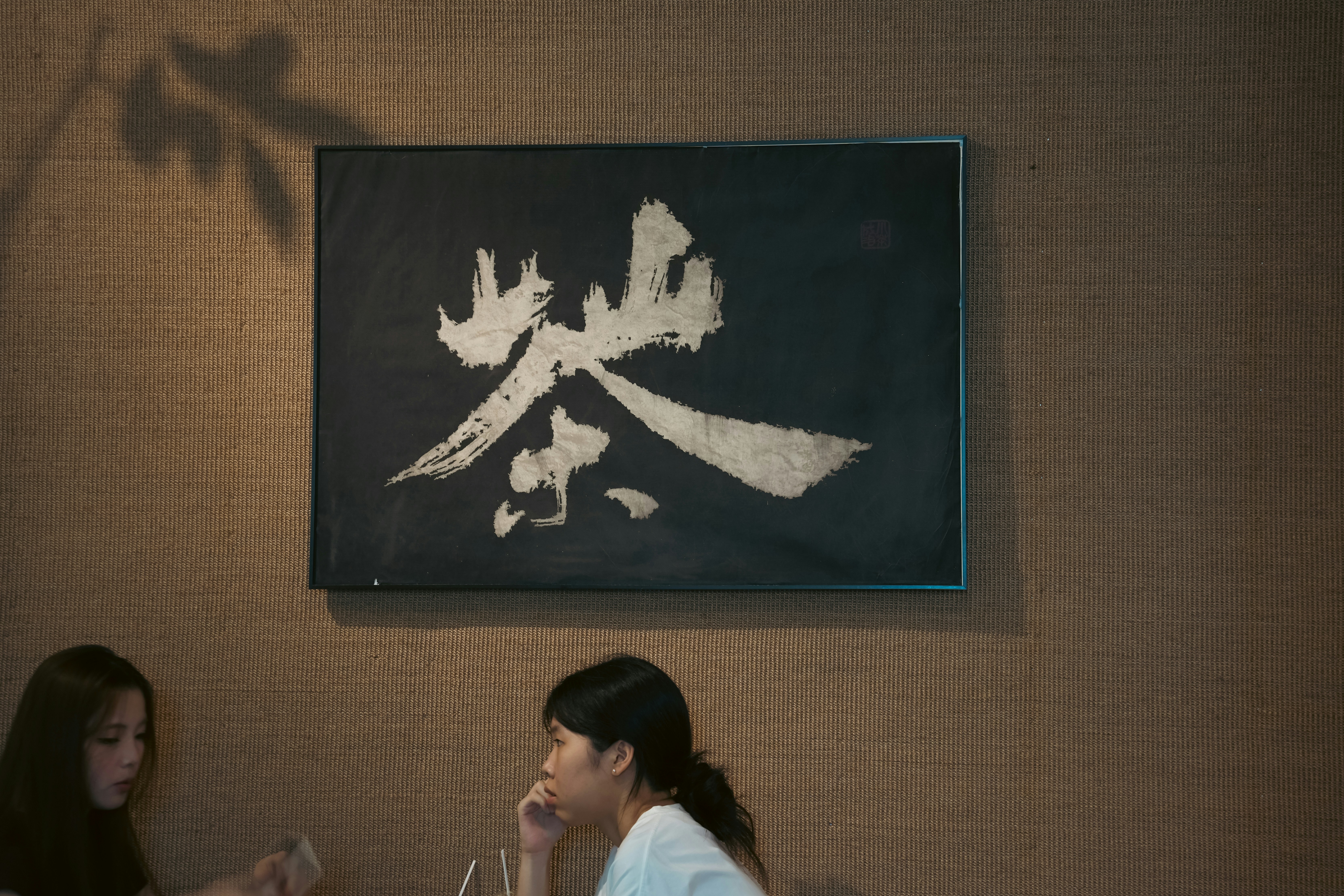 Quiet Conversation under a Framed Calligraphy
