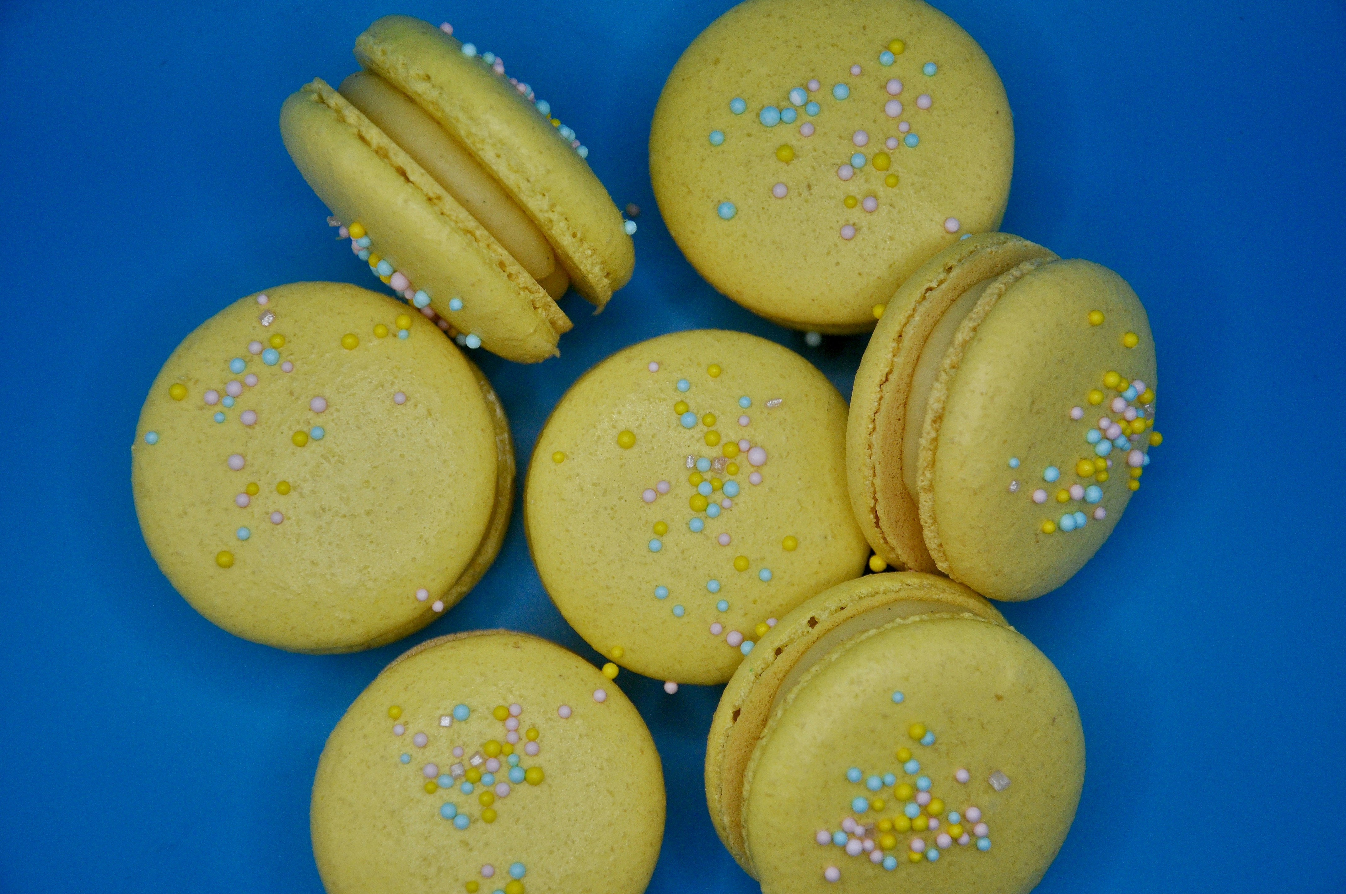 Sunny Delights: A Scatter of Yellow Macarons on a Blue Canvas