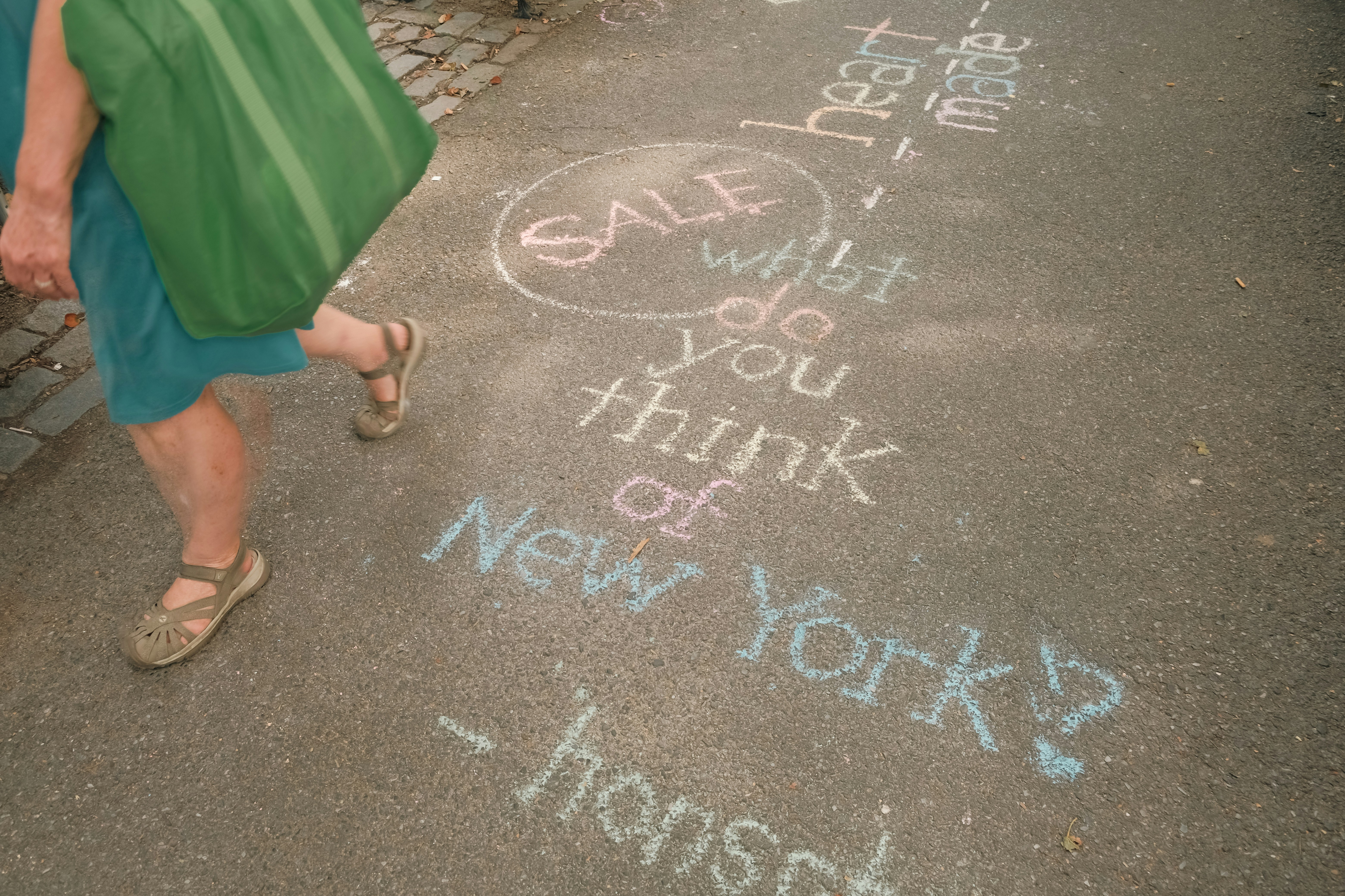Chalked Wonder on a Sidewalk: A Pedestrian Passes by a Message from NYC