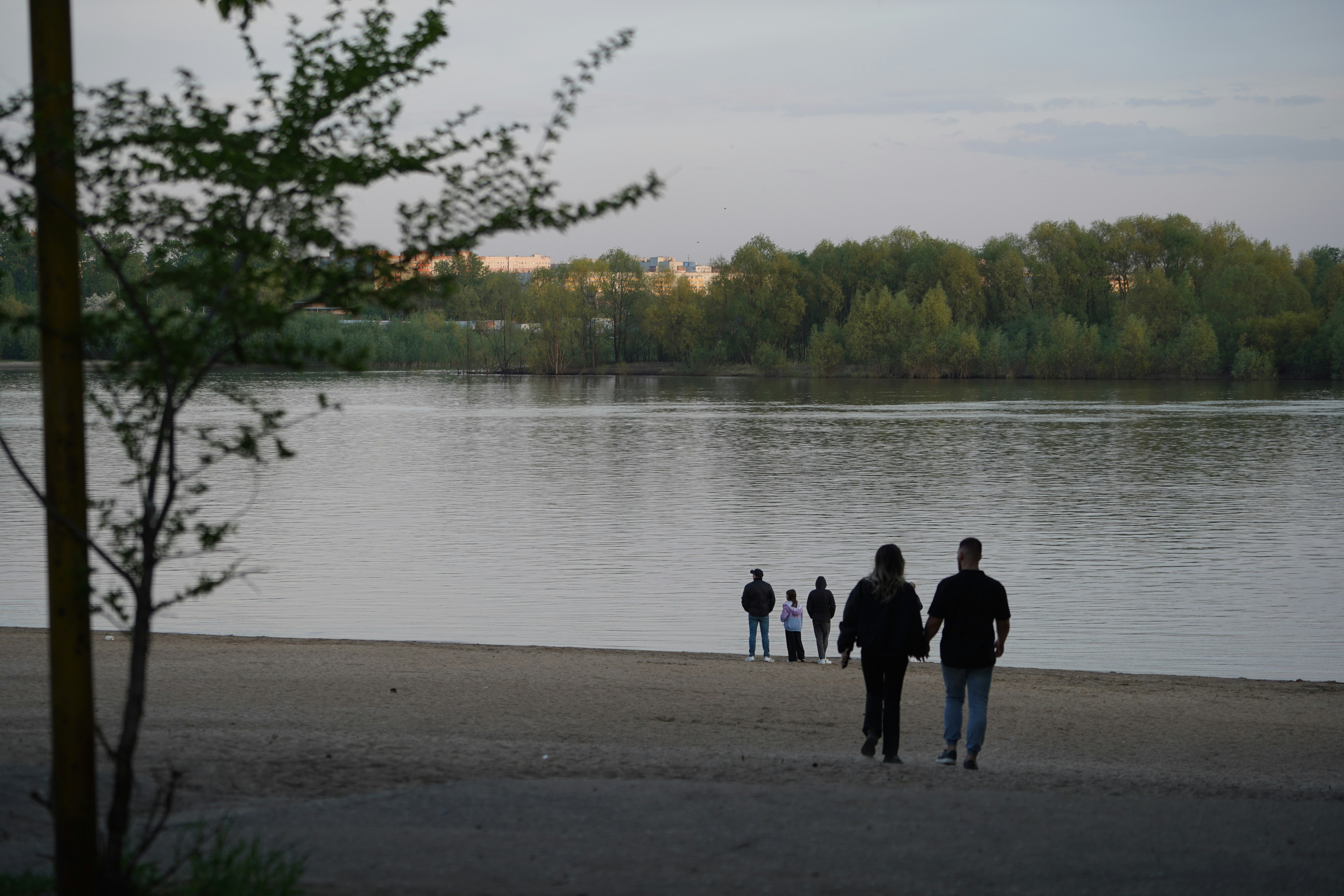 Pair of walkers along a tranquil lakeside at dusk