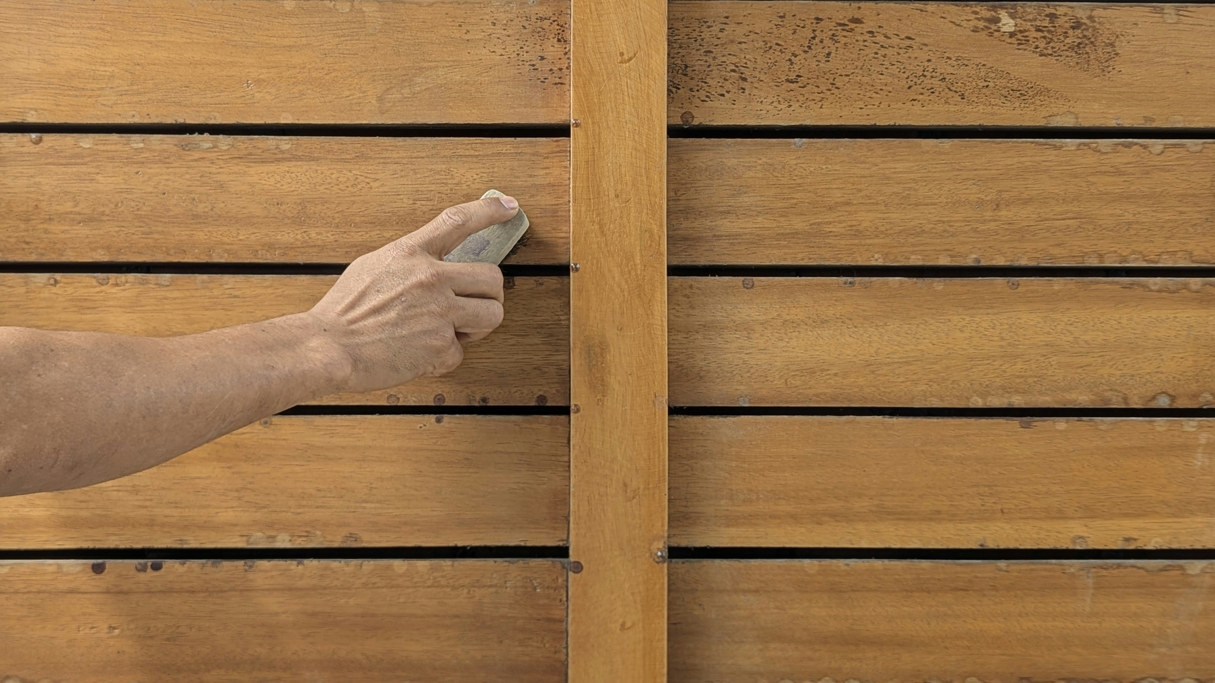 Hand Gripping a Tool Across Wooden Slats