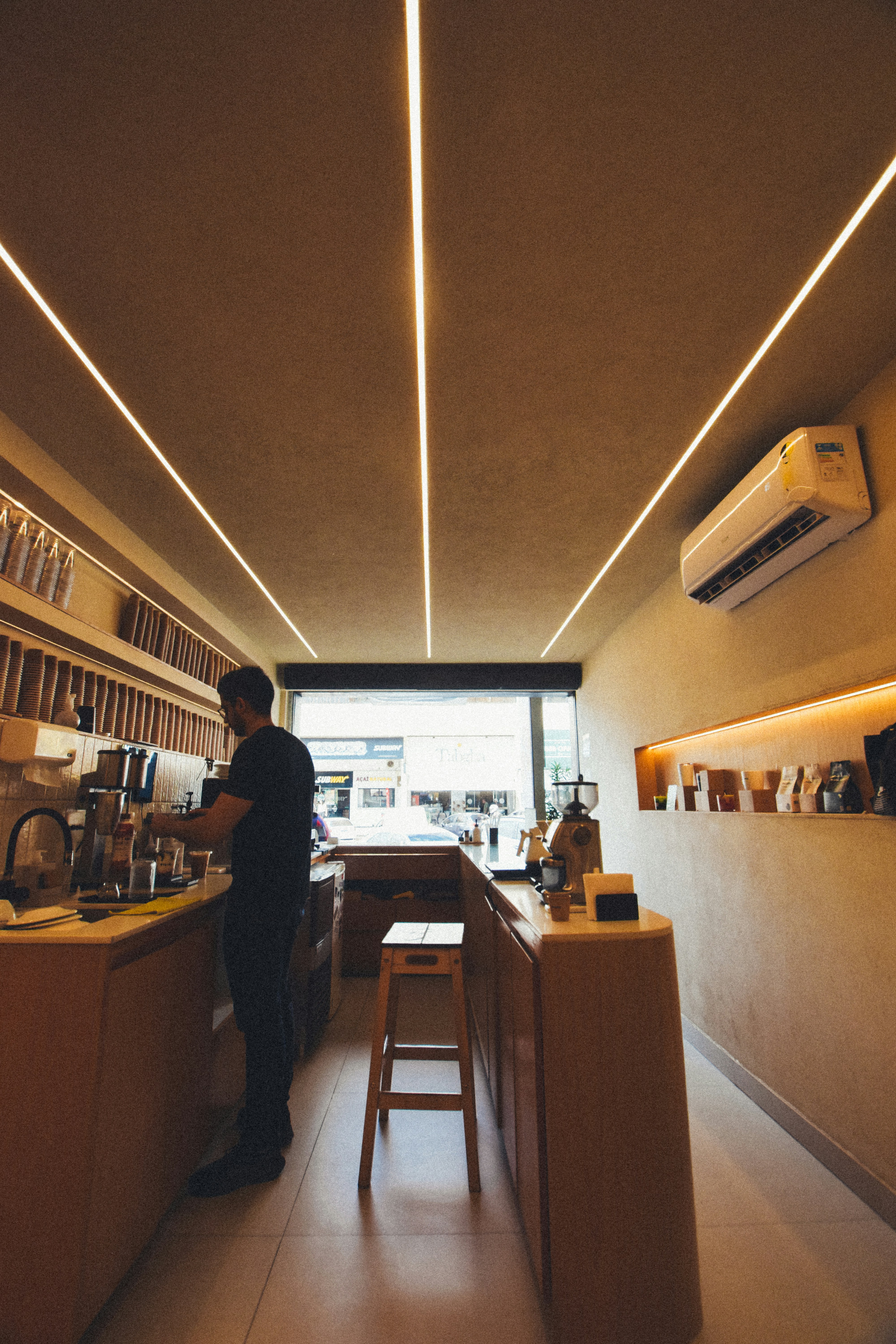 Narrow Cafe Hour: Barista at Work Under Neon Lines