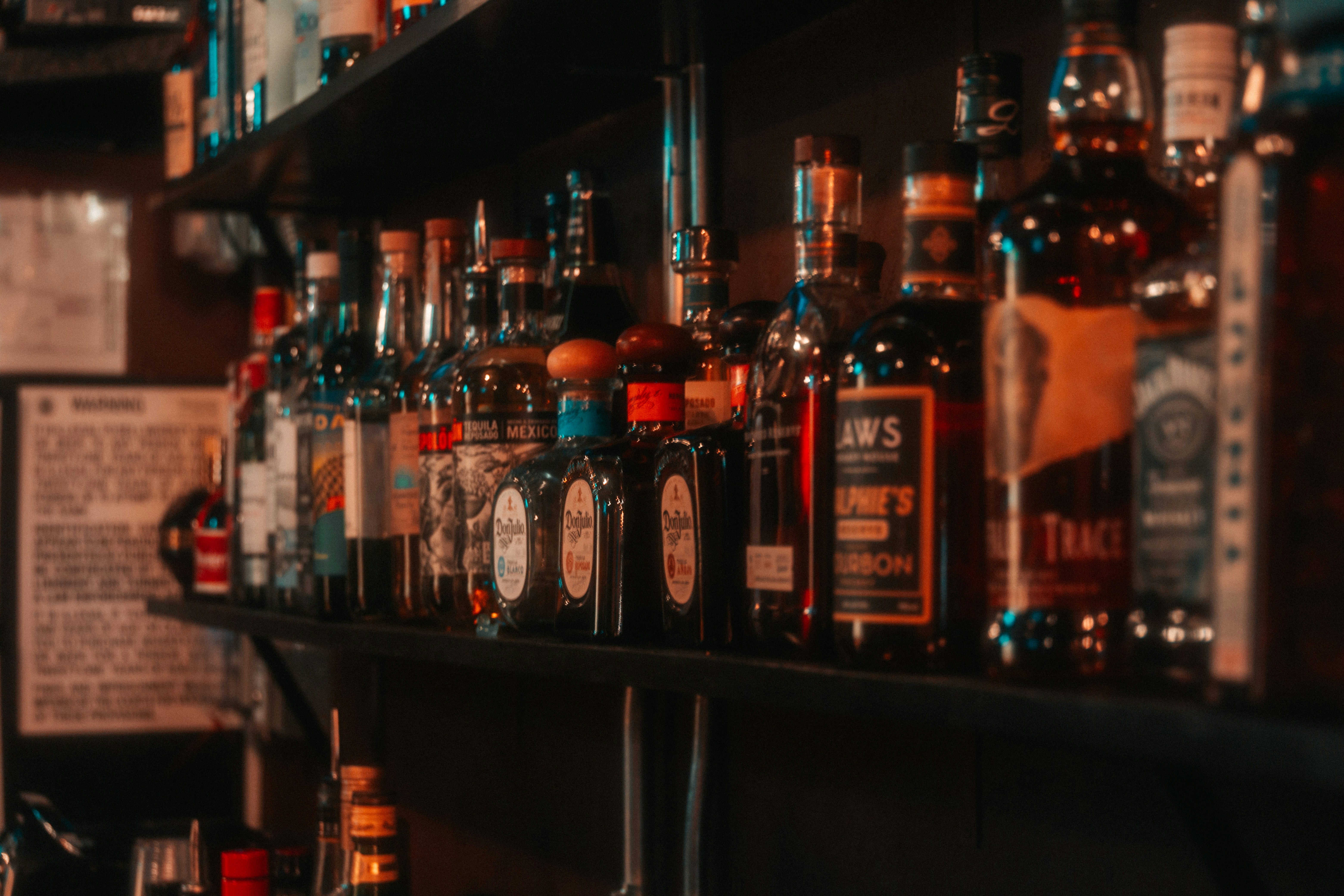 Shelved Spirits: Row of Bottles Casting Warm Glow