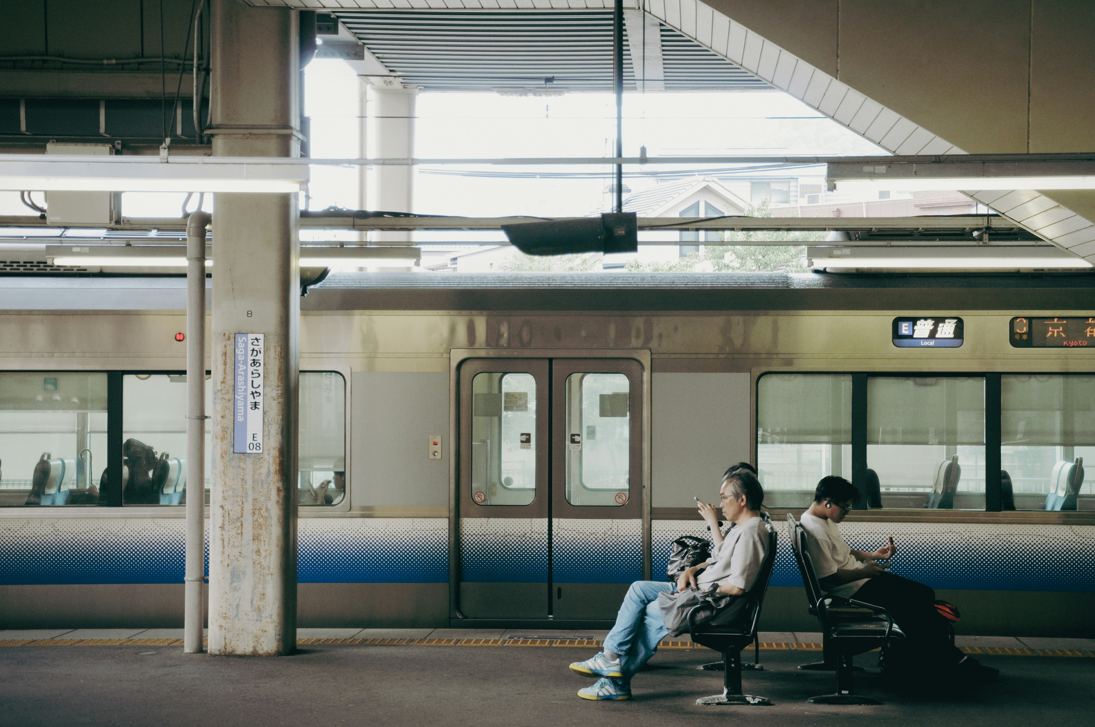 Quiet Pause on a Platform: Two Travelers, One Shared Screen