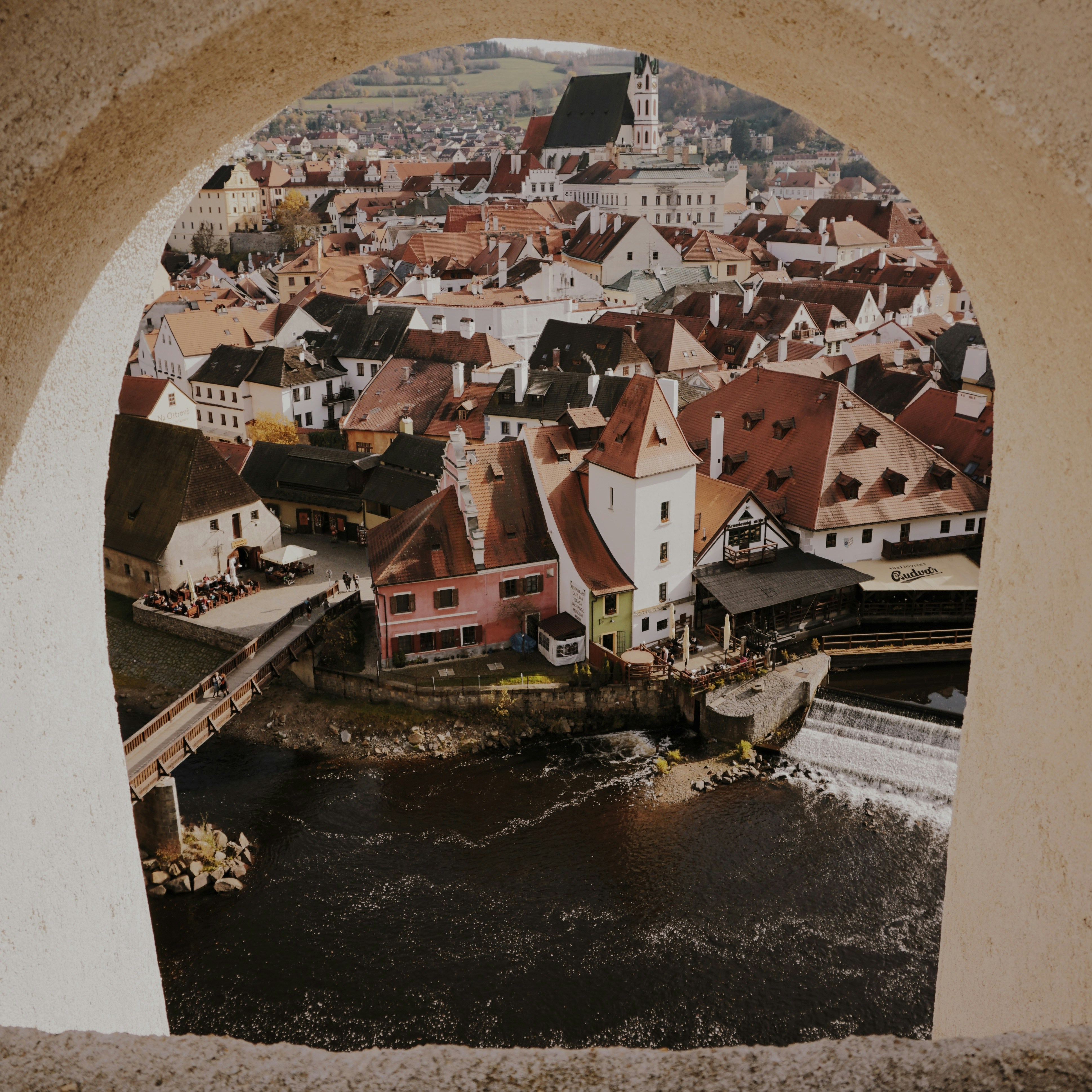 Cobbled town beneath a stone arch: riverside rooftops in warm light
