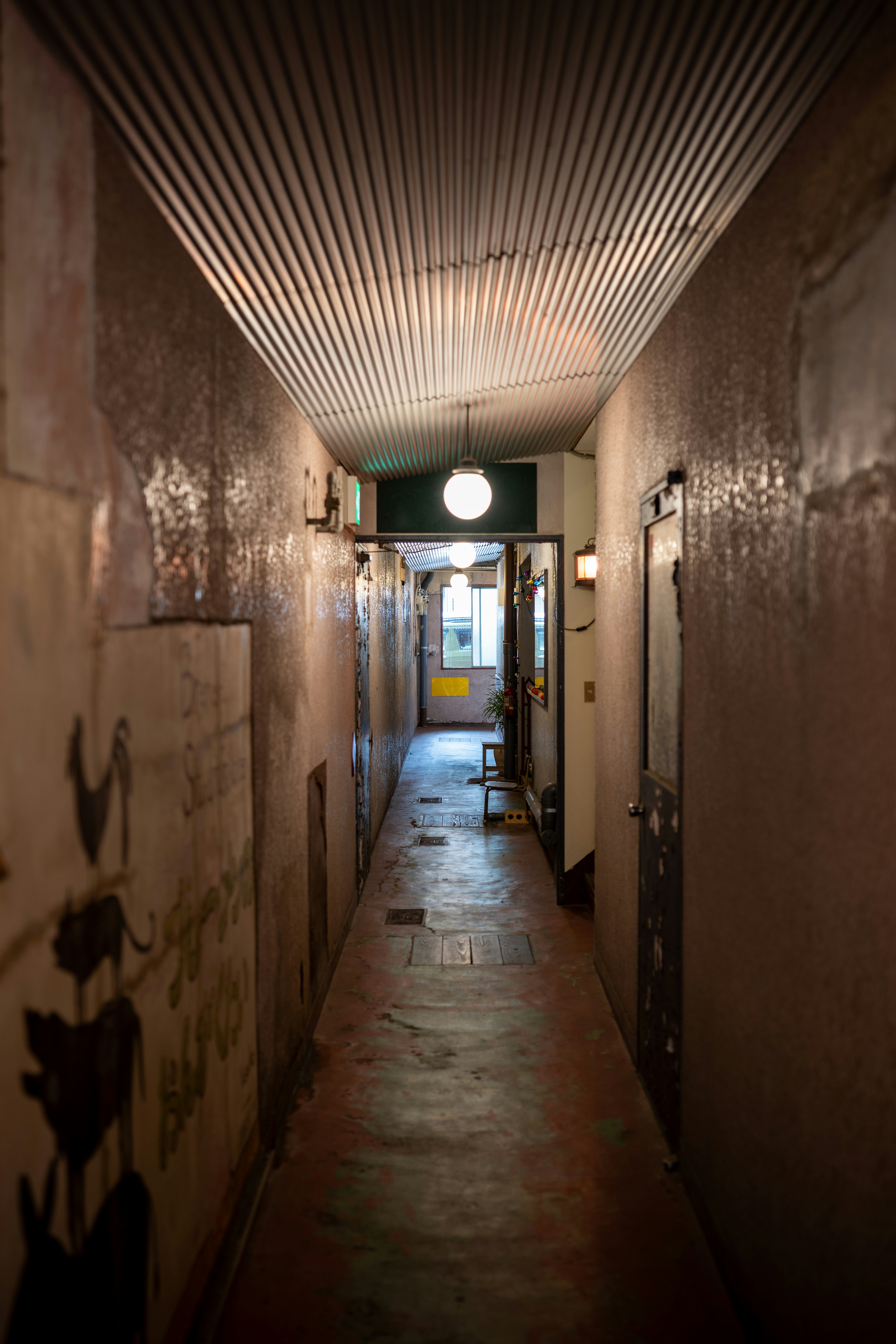 A Narrow Corridor into Light: Basement Hallway with Overhead Paneling