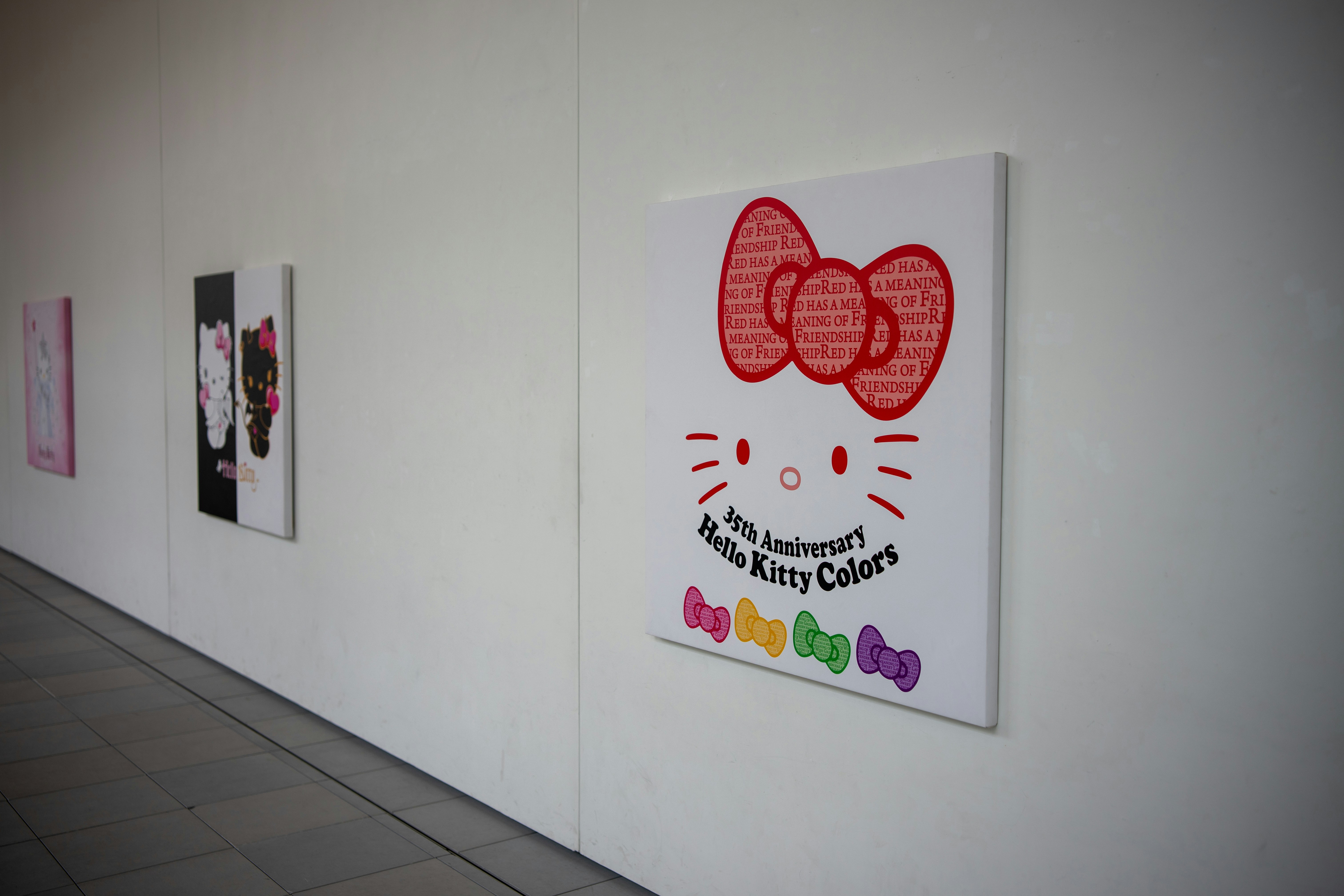 Hello Kitty art show: white canvas with red bow on gallery wall