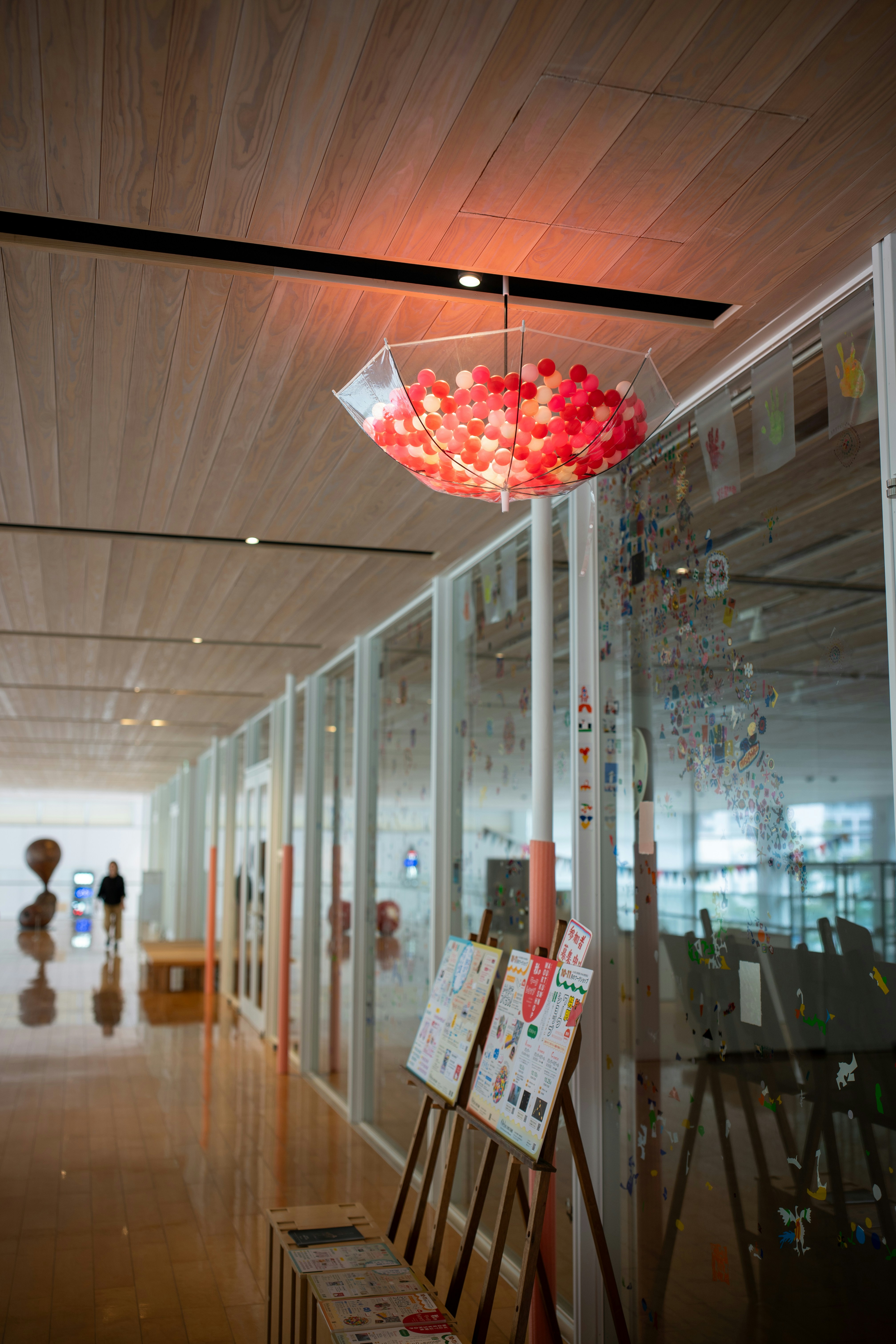 Floating red orbs: a suspended art installation in a sunlit gallery corridor