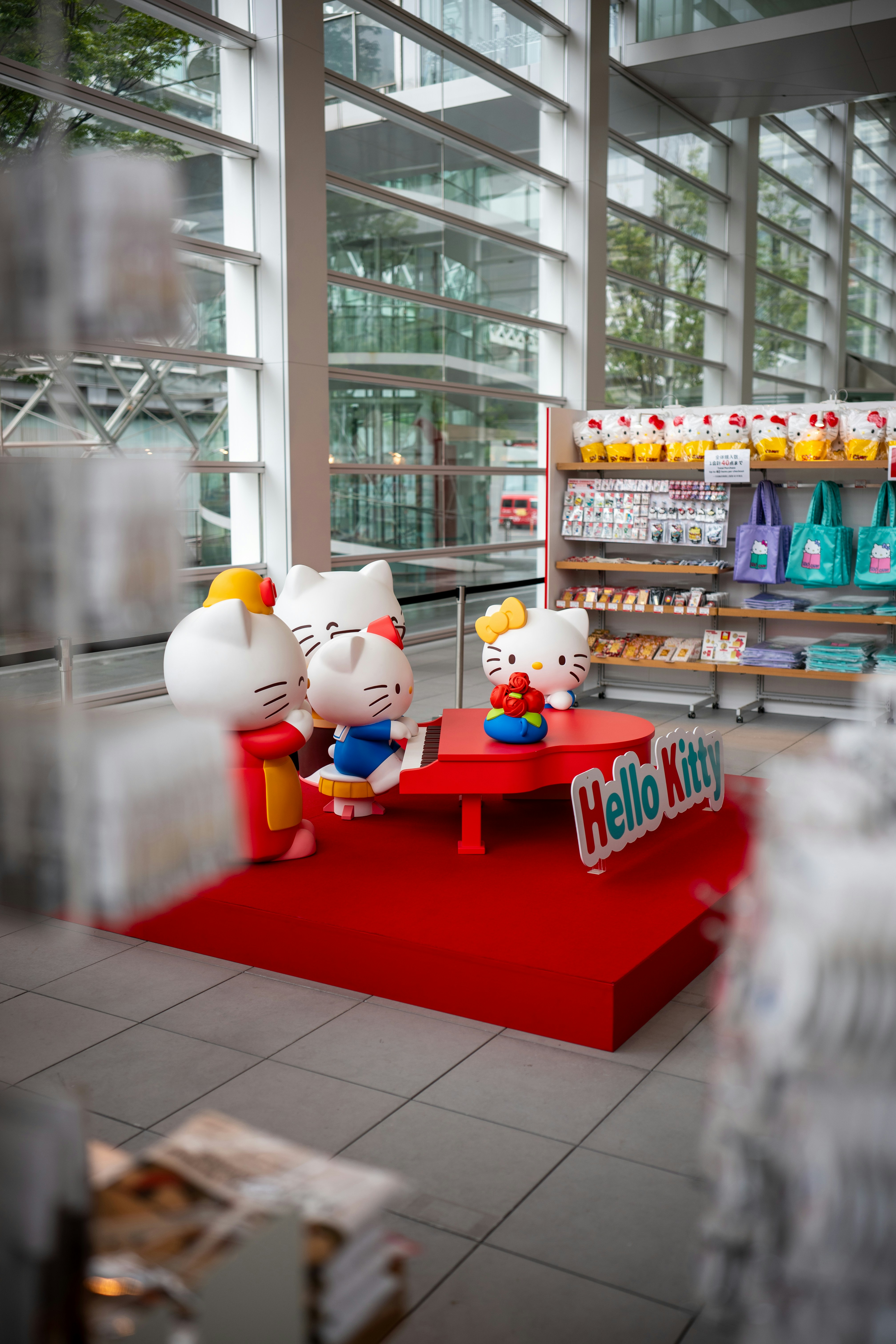 Hello Kitty Stage: Plush superheroes gathered around a red table inside a modern atrium
