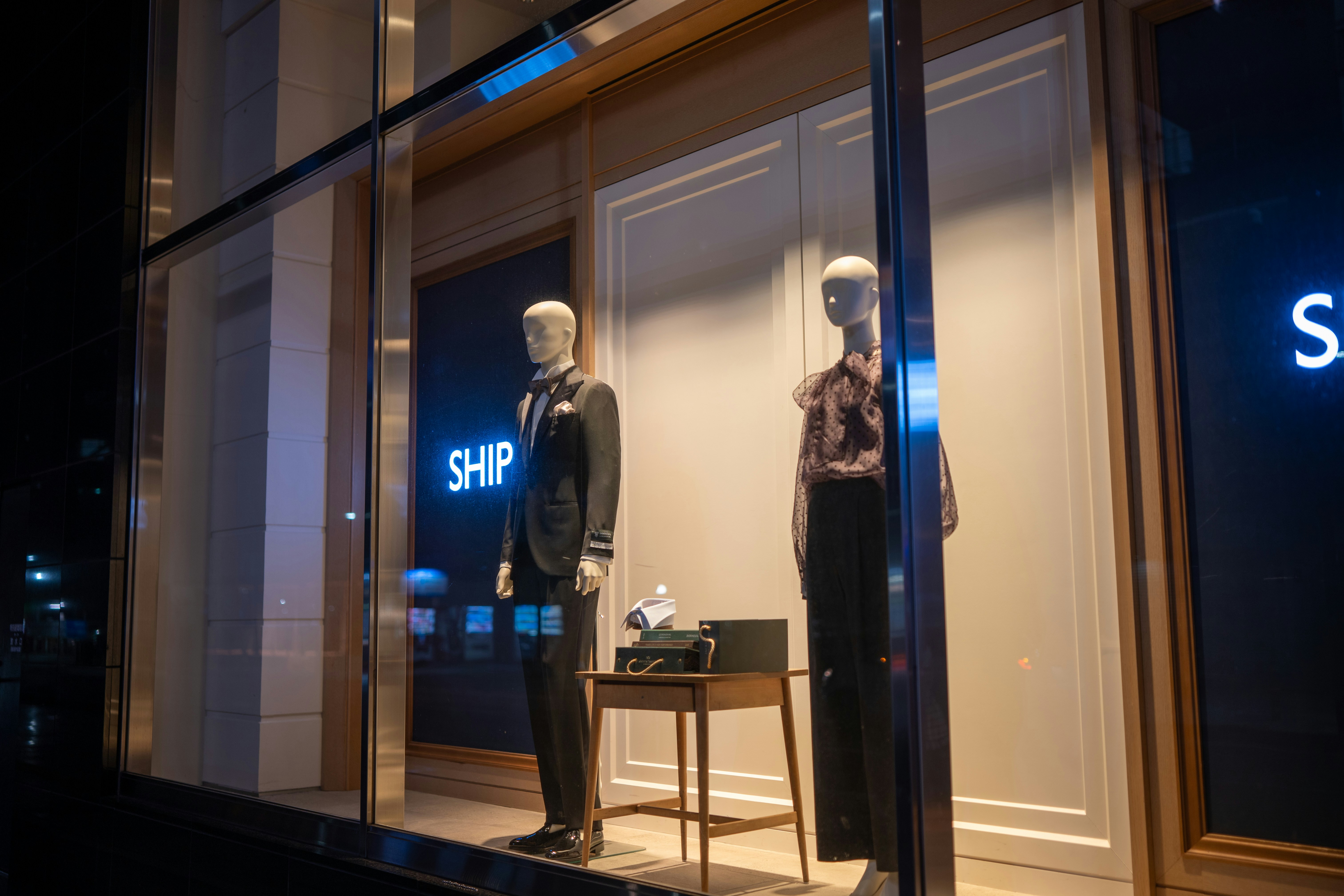 Glassed Ambitions: Mannequins in a Neon-Outlined Shopfront