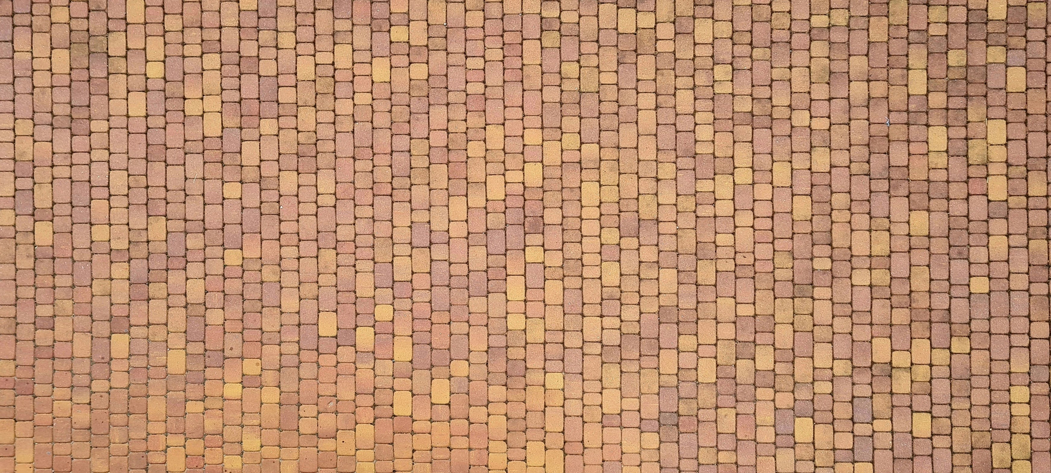 Patterned ceramic tiles in warm ochre and amber create a uniform mosaic across the frame. A close-up of architectural tiling emphasizing rhythm and texture.