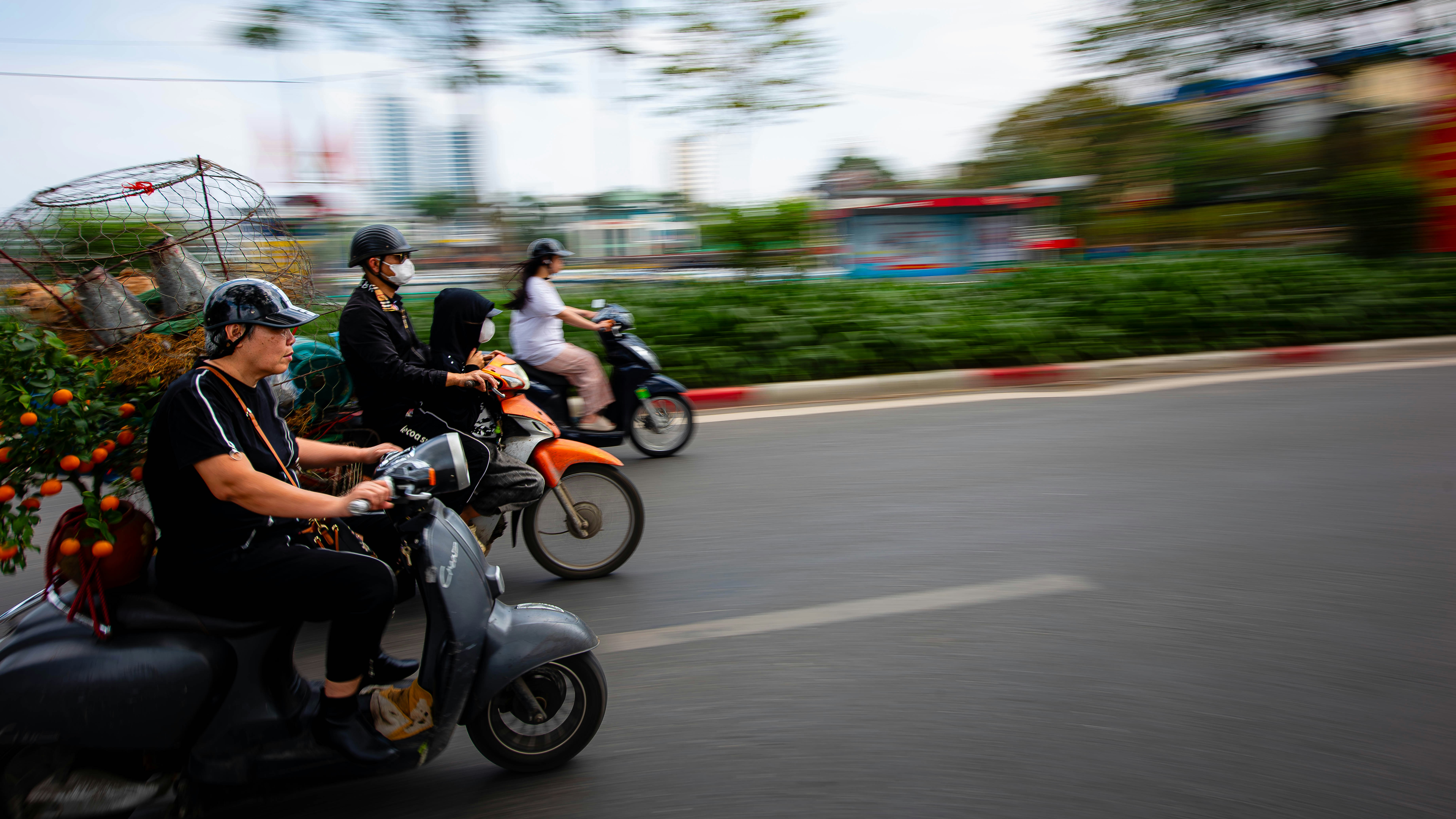 Motion in the Bangkok Boulevard: Scooters Cutting Through a Blur of Green