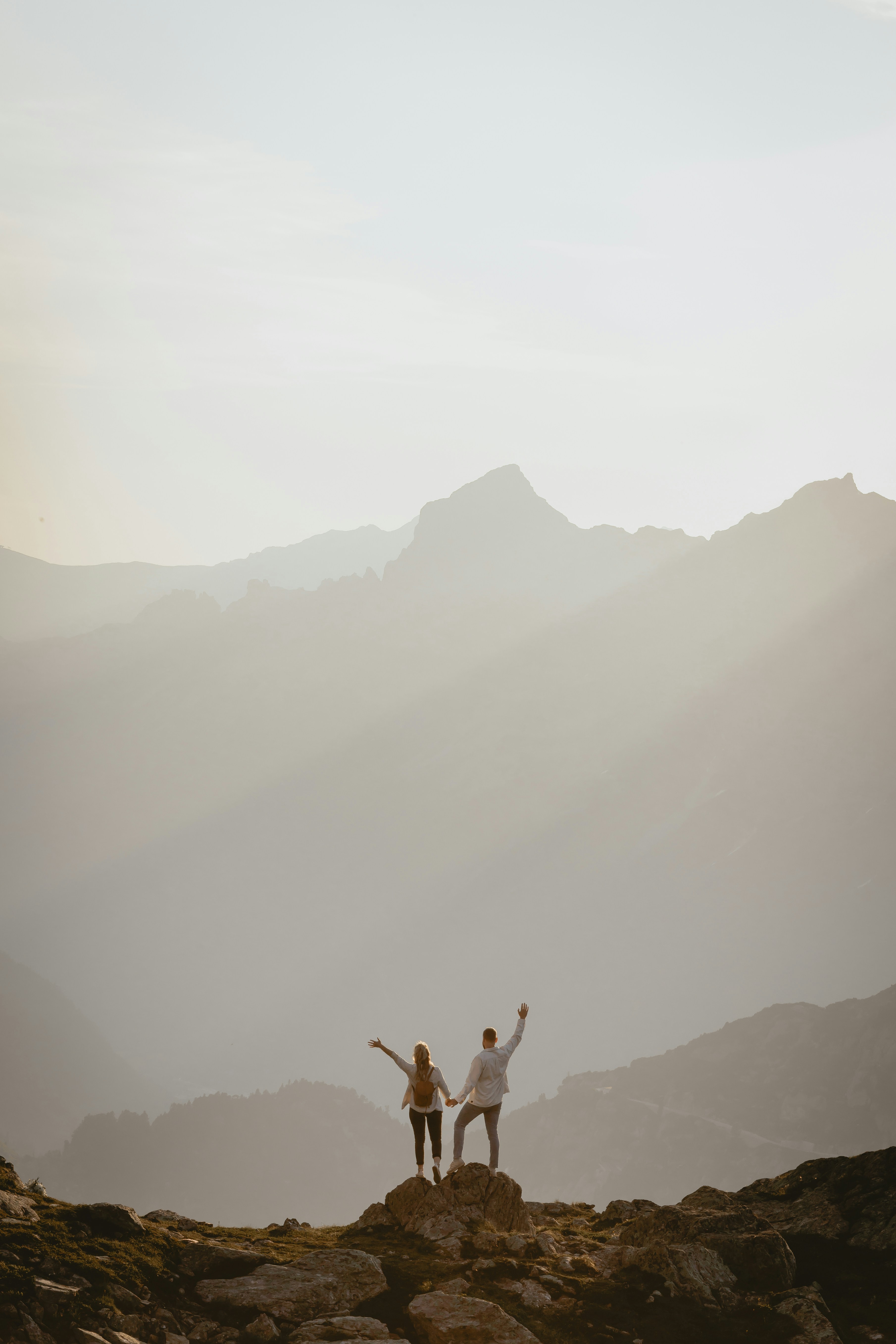 Sunlit Summit: Two Travelers Reaching Toward the Horizon