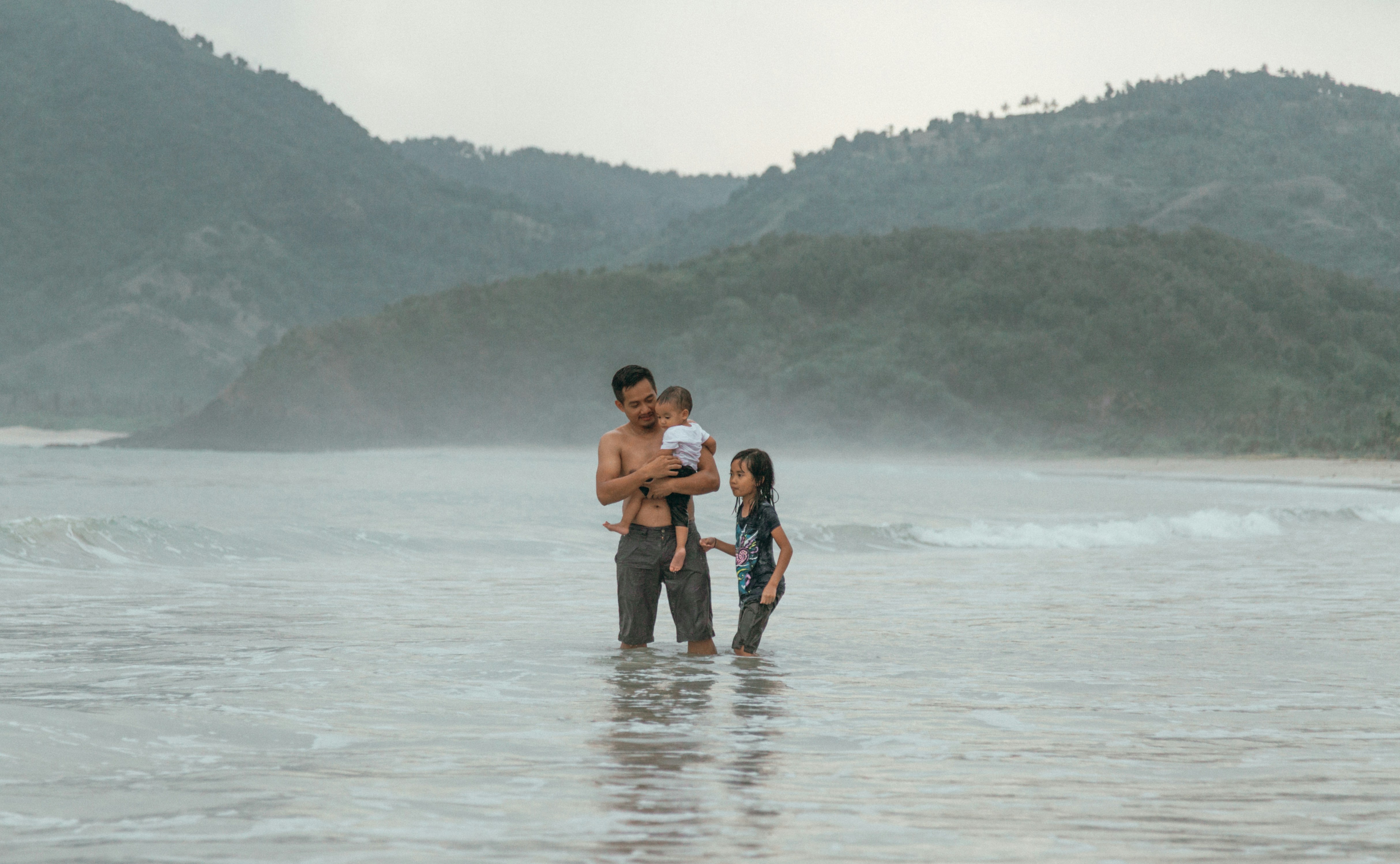 Holding Hope: A Family's Quiet Moment Amid Gentle Surf