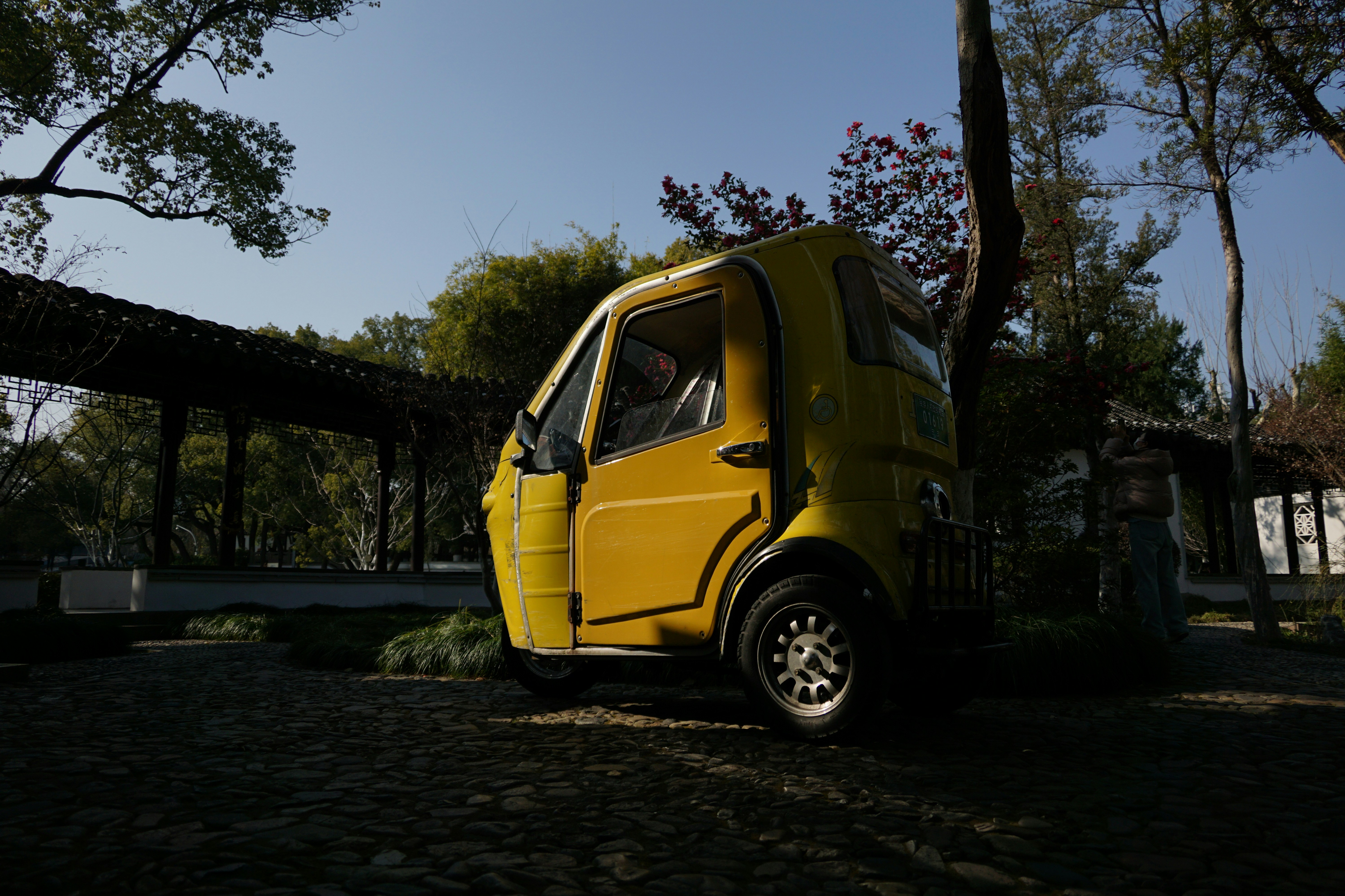 Yellow micro truck under a shaded canopy: a quiet roadside portrait