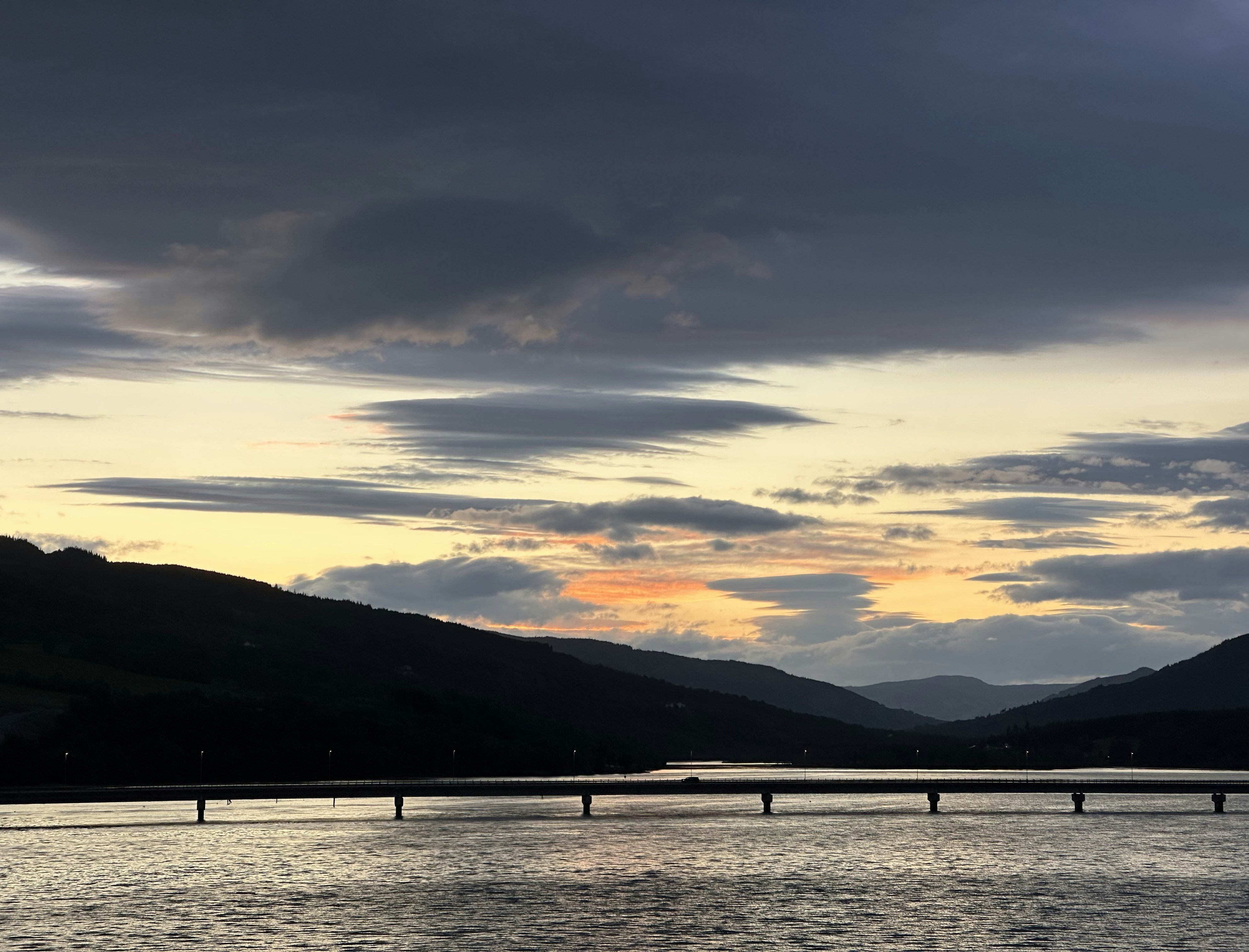 Dusk Over the Bridge: Calm Waters and Silhouetted Hills