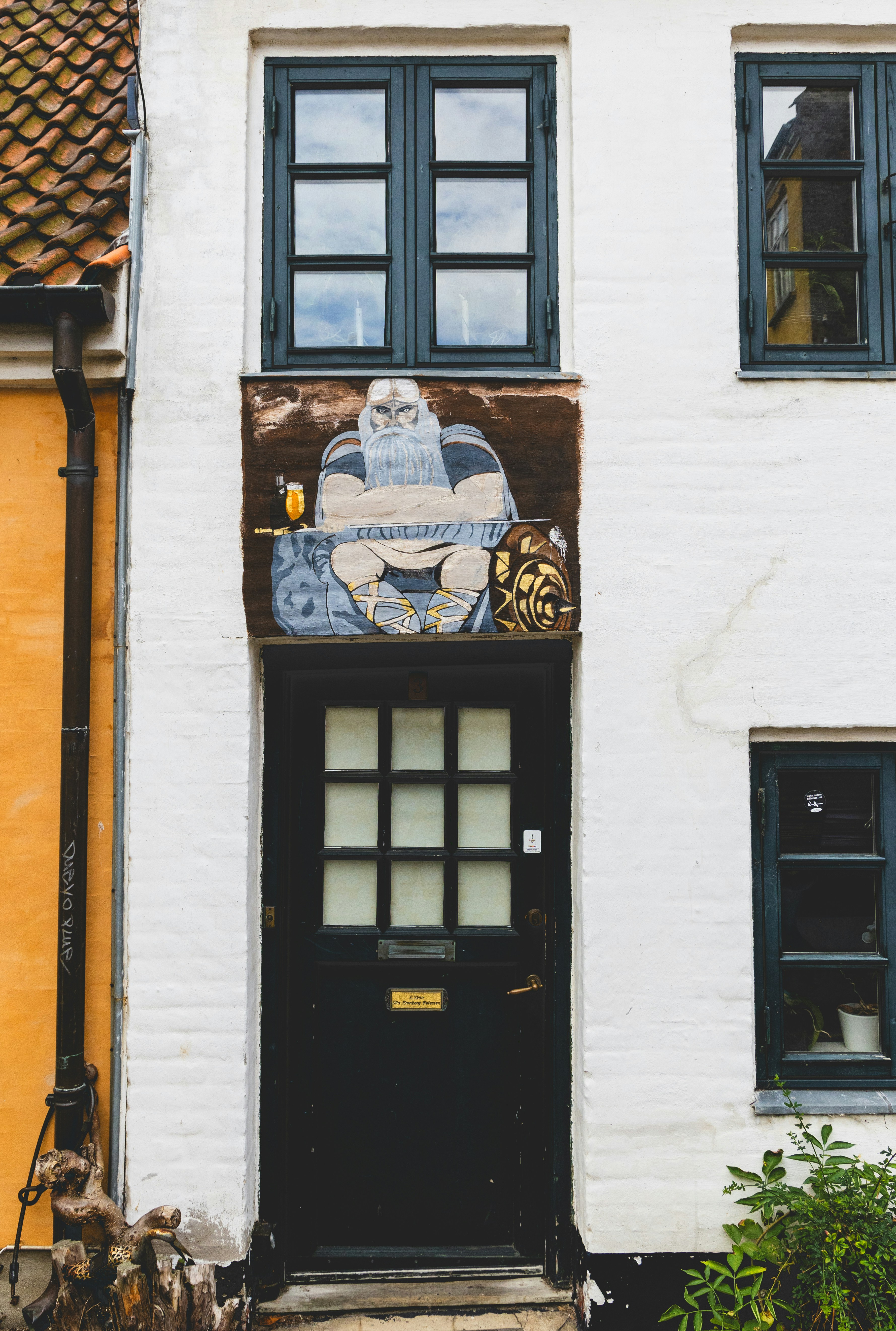 Gabled Murals: A Bearded Figure Above a Black Door