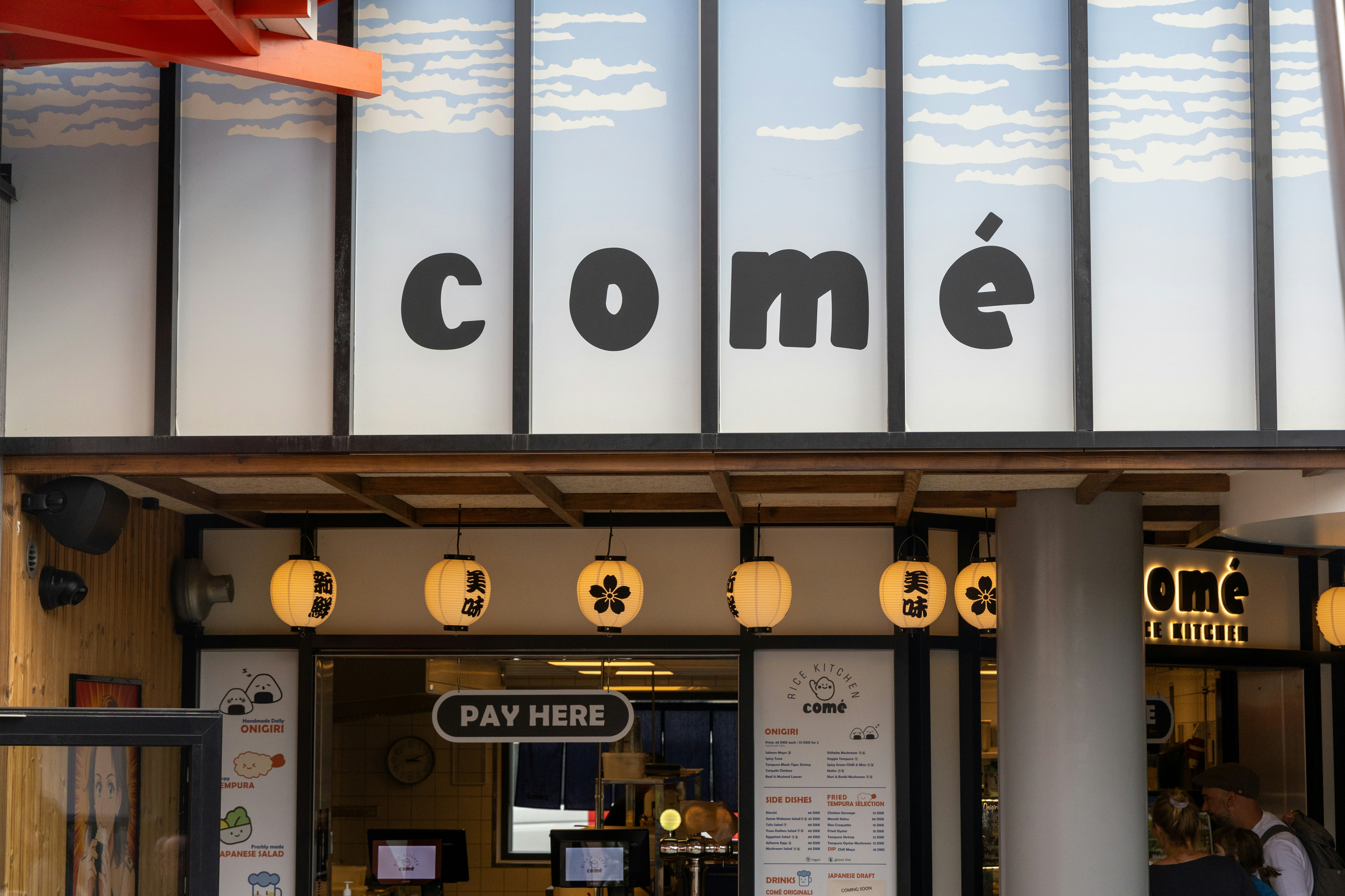 comaÉ storefront glow: calm cafe beneath a bright sign