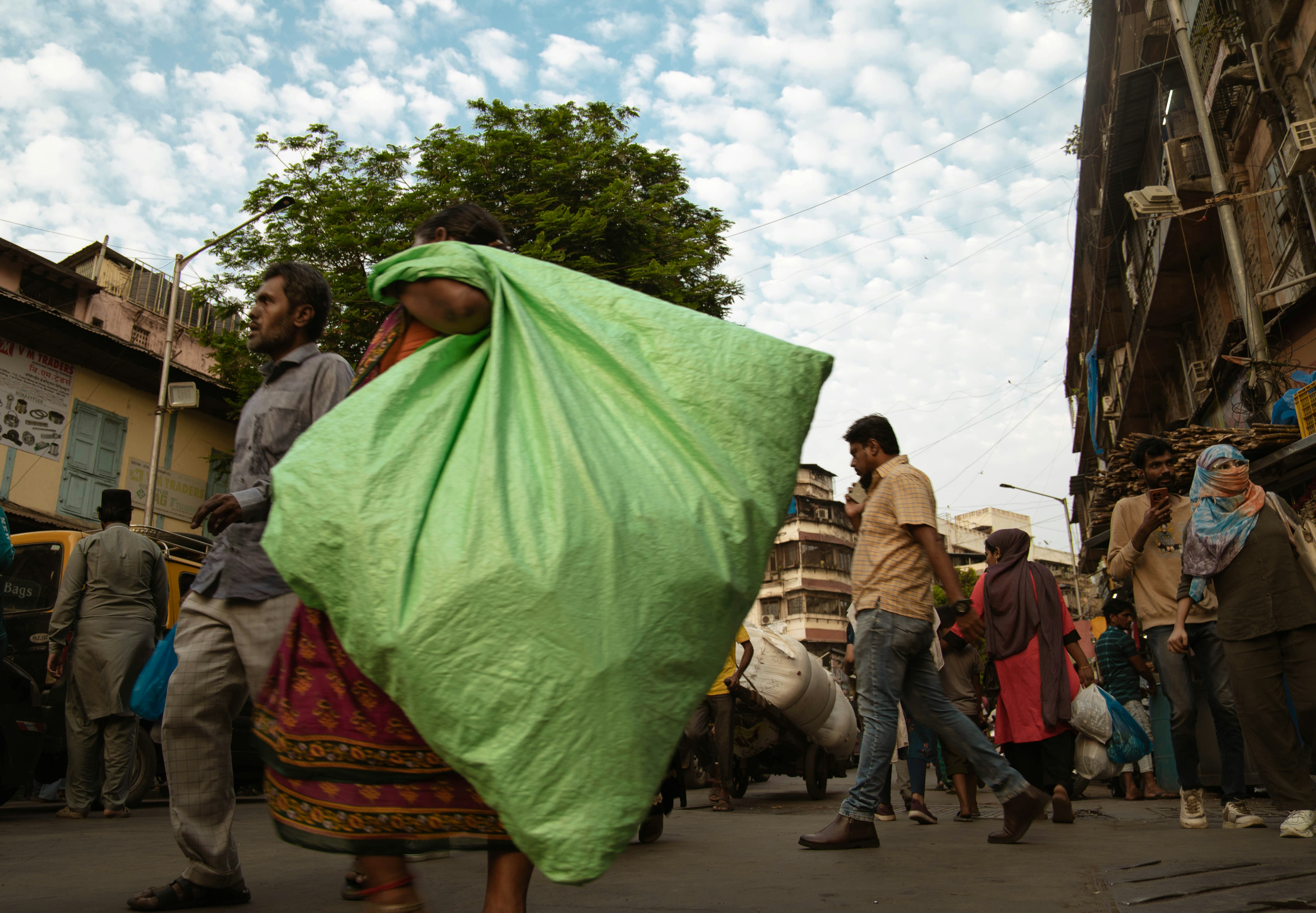 Green veil in motion: a bustling street scene with pedestrians