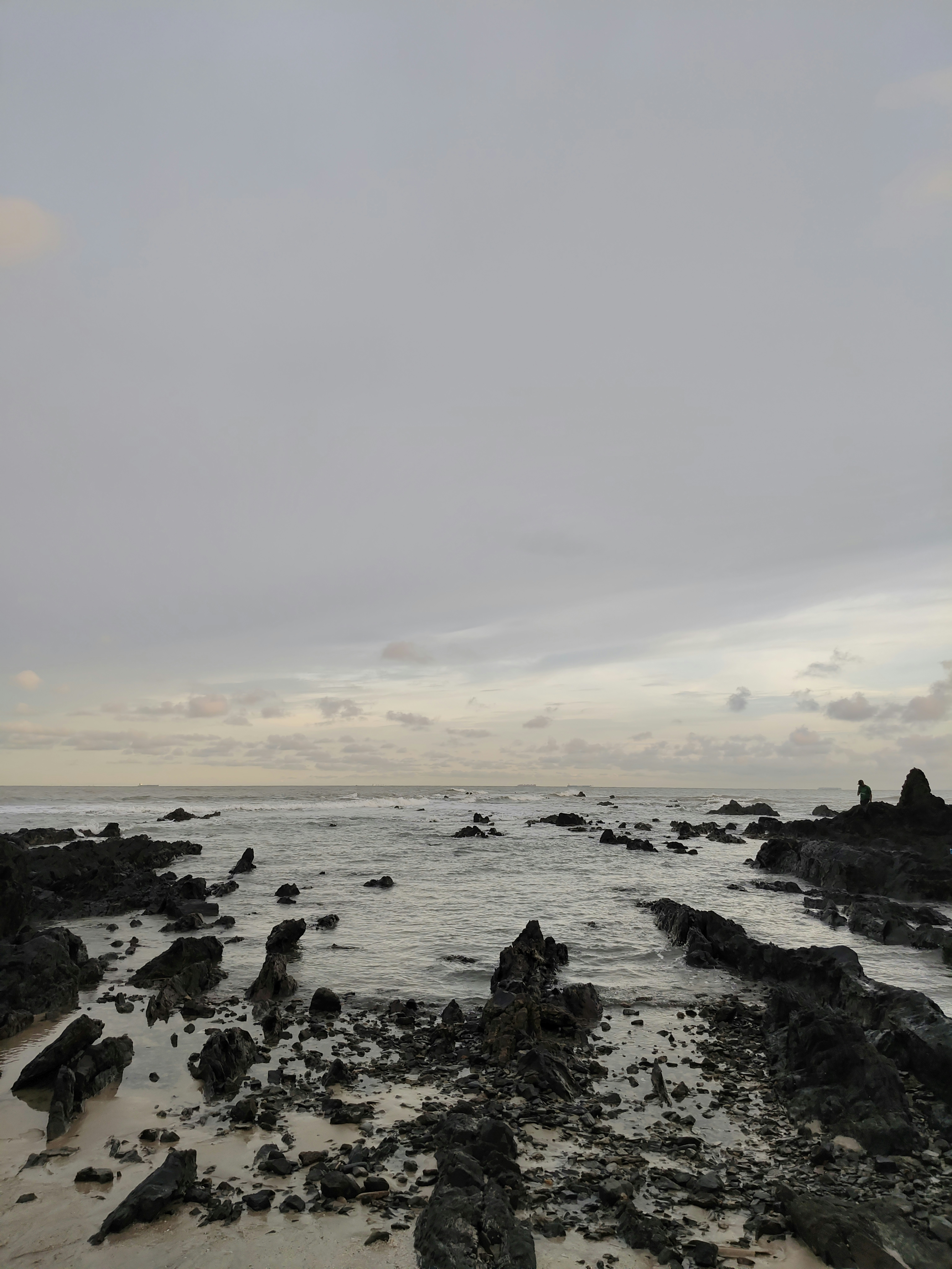 Rugged shoreline at dusk: jagged rocks whisper to the tide
