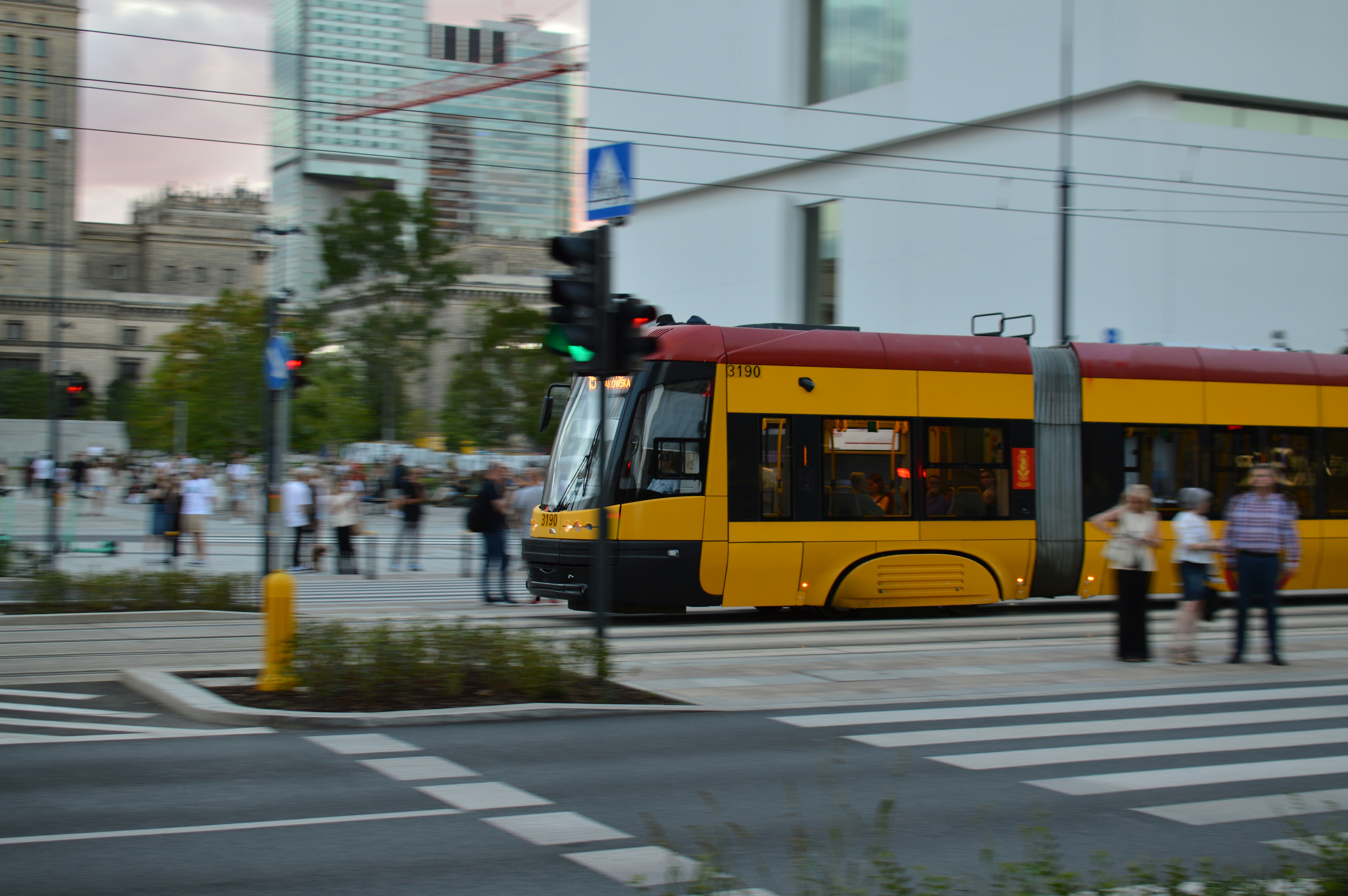 City tram in motion past a pedestrian-filled crosswalk