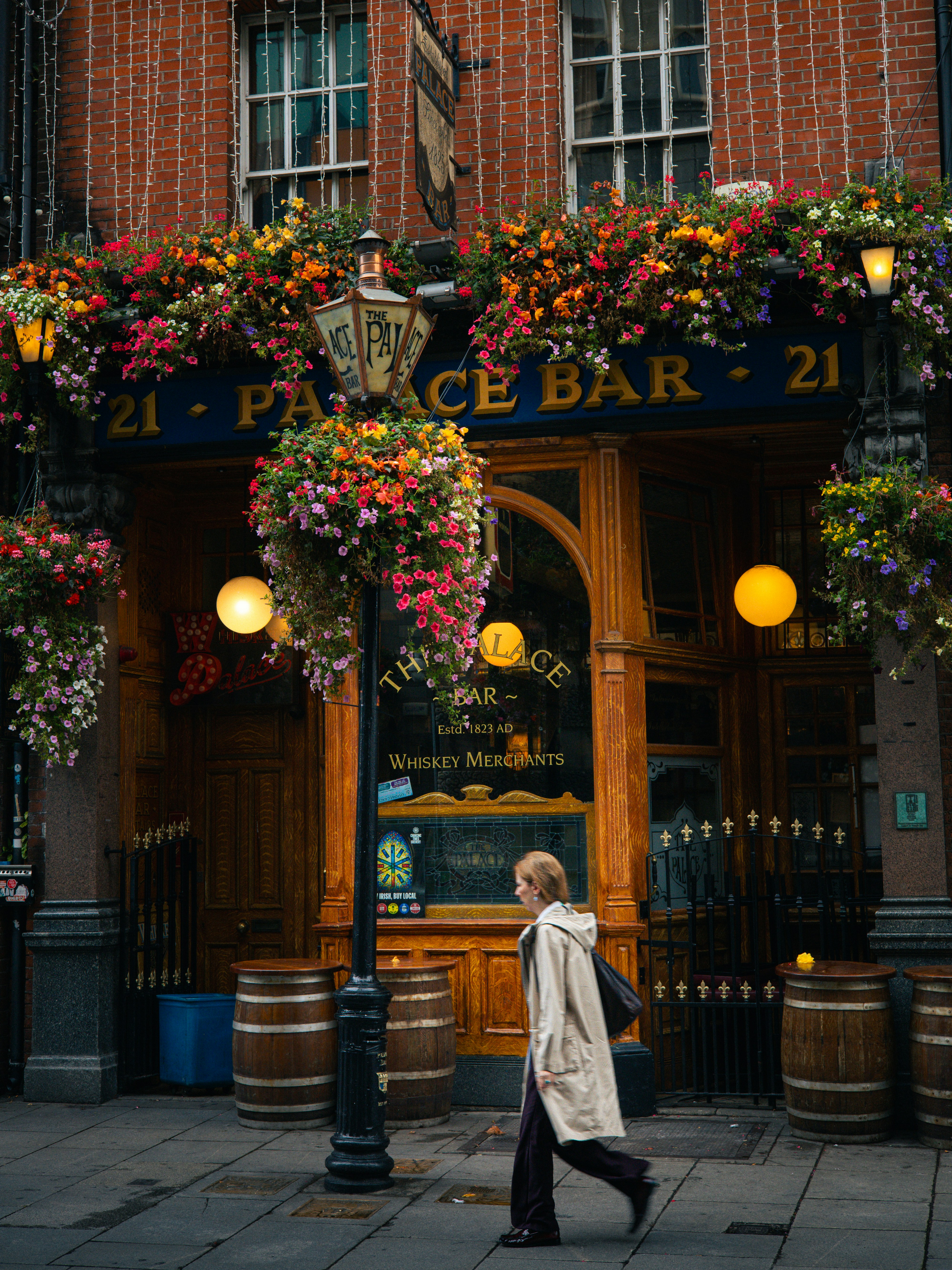 Pedestrian in front of a floral pub façade at golden hour