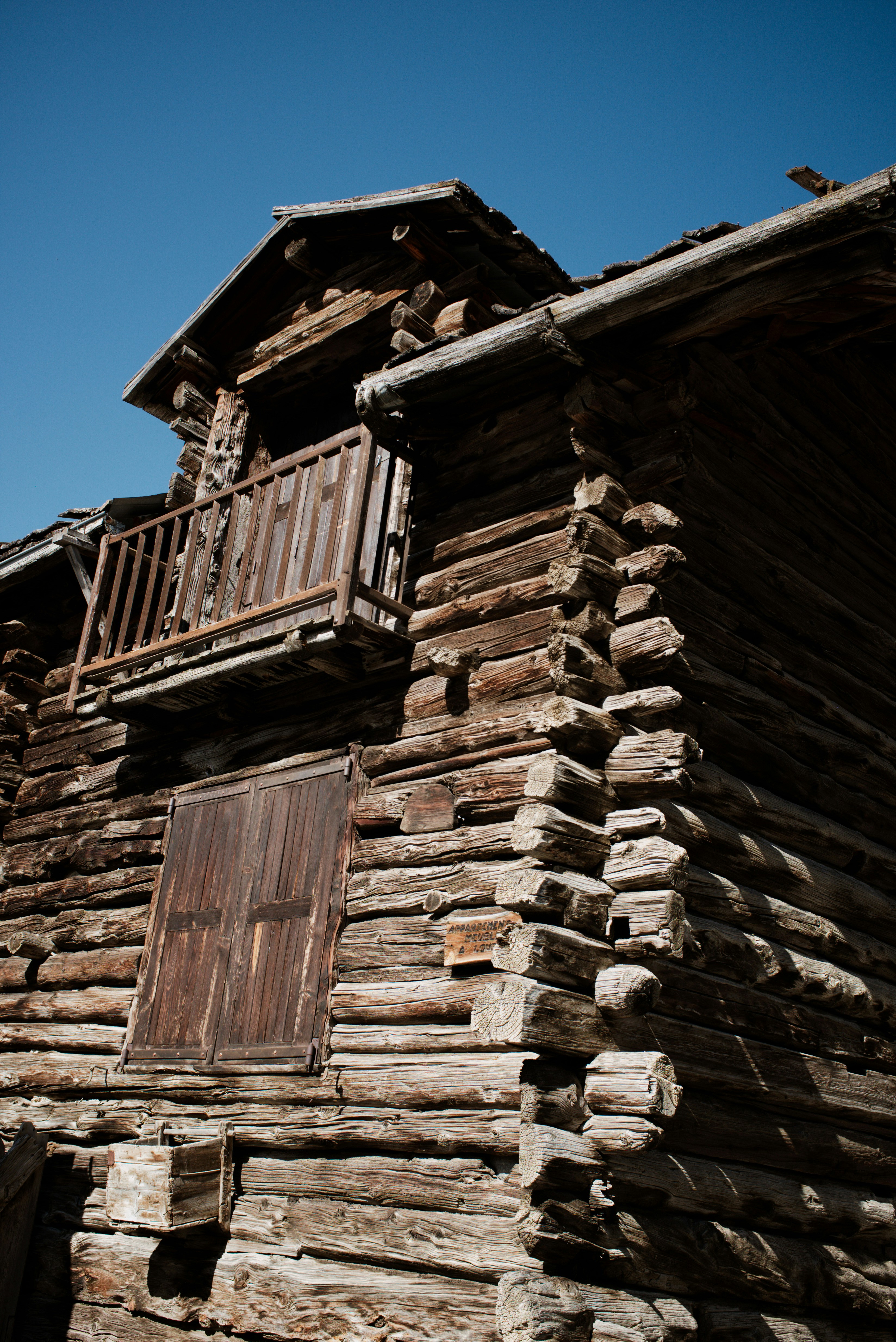 Weathered Balcony Over a Log Cabin under a Clear Sky