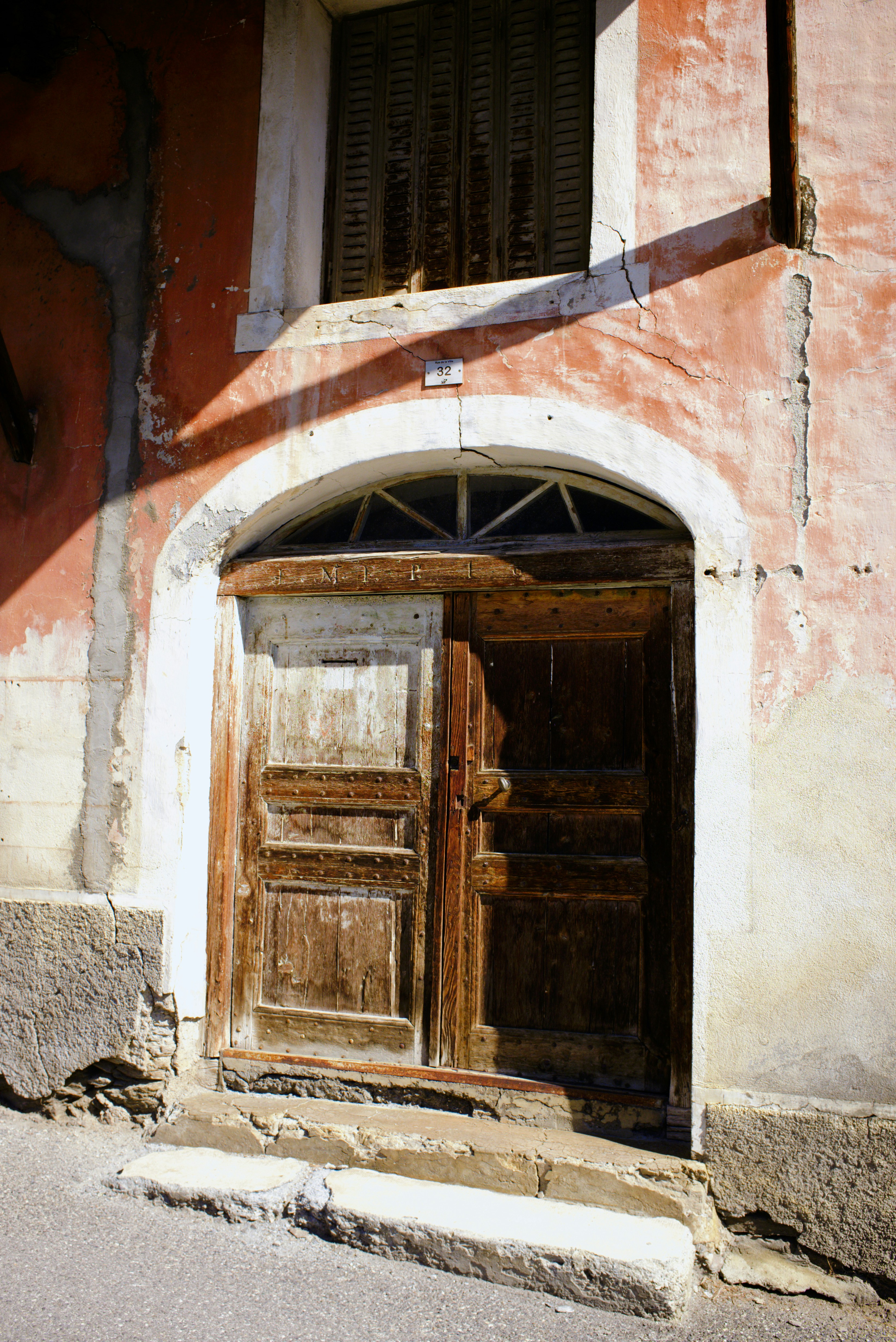 Weathered doorway under a sunlit arch in a faded orange facade