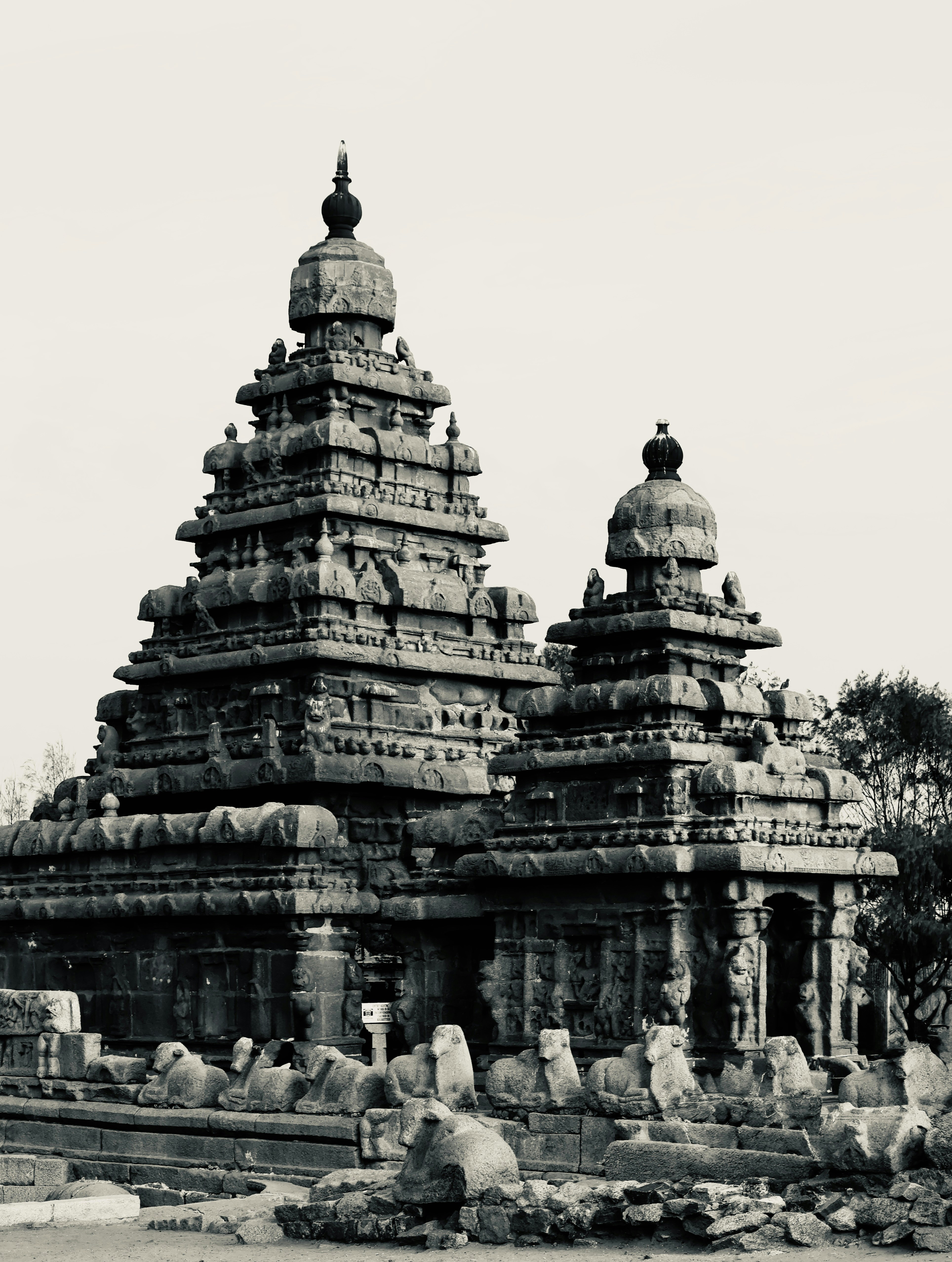 Monochrome temple complex with layered spires and stone figures, captured in serene daylight.
