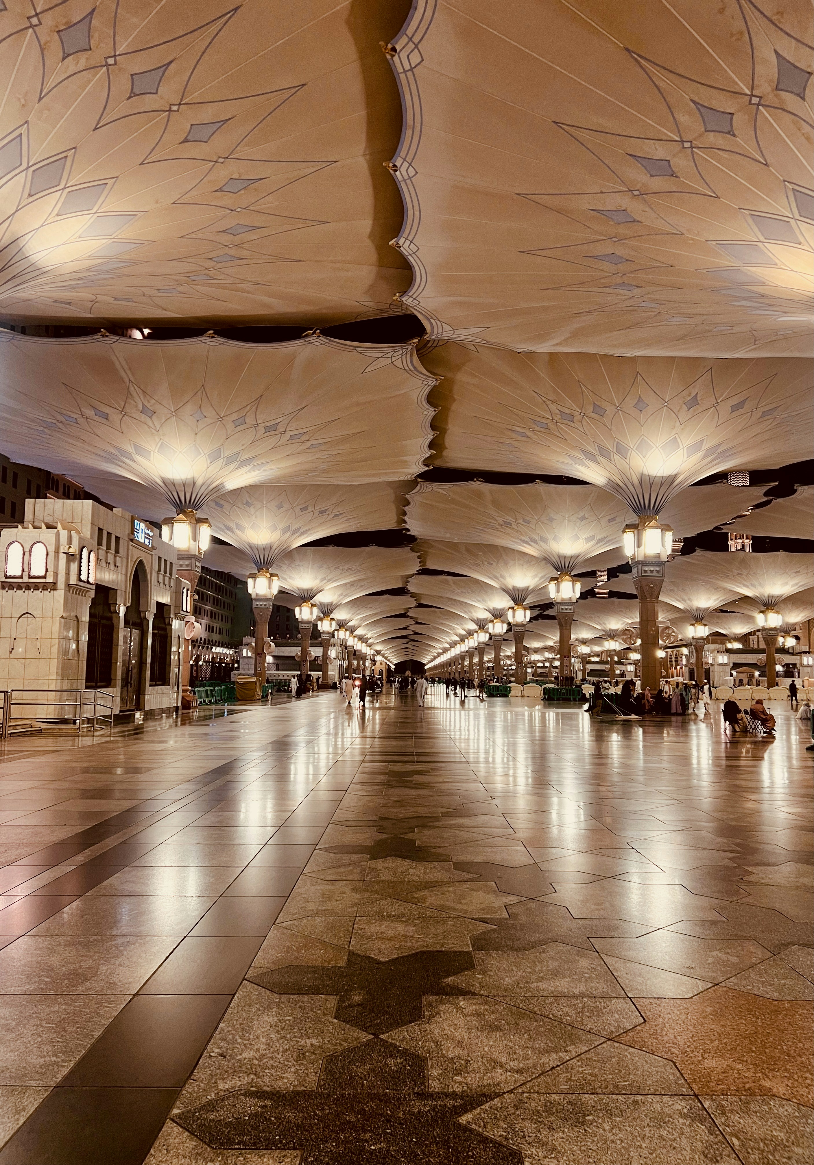 Large retractable umbrellas shading a wide stone plaza at the Prophet's Mosque in Medina