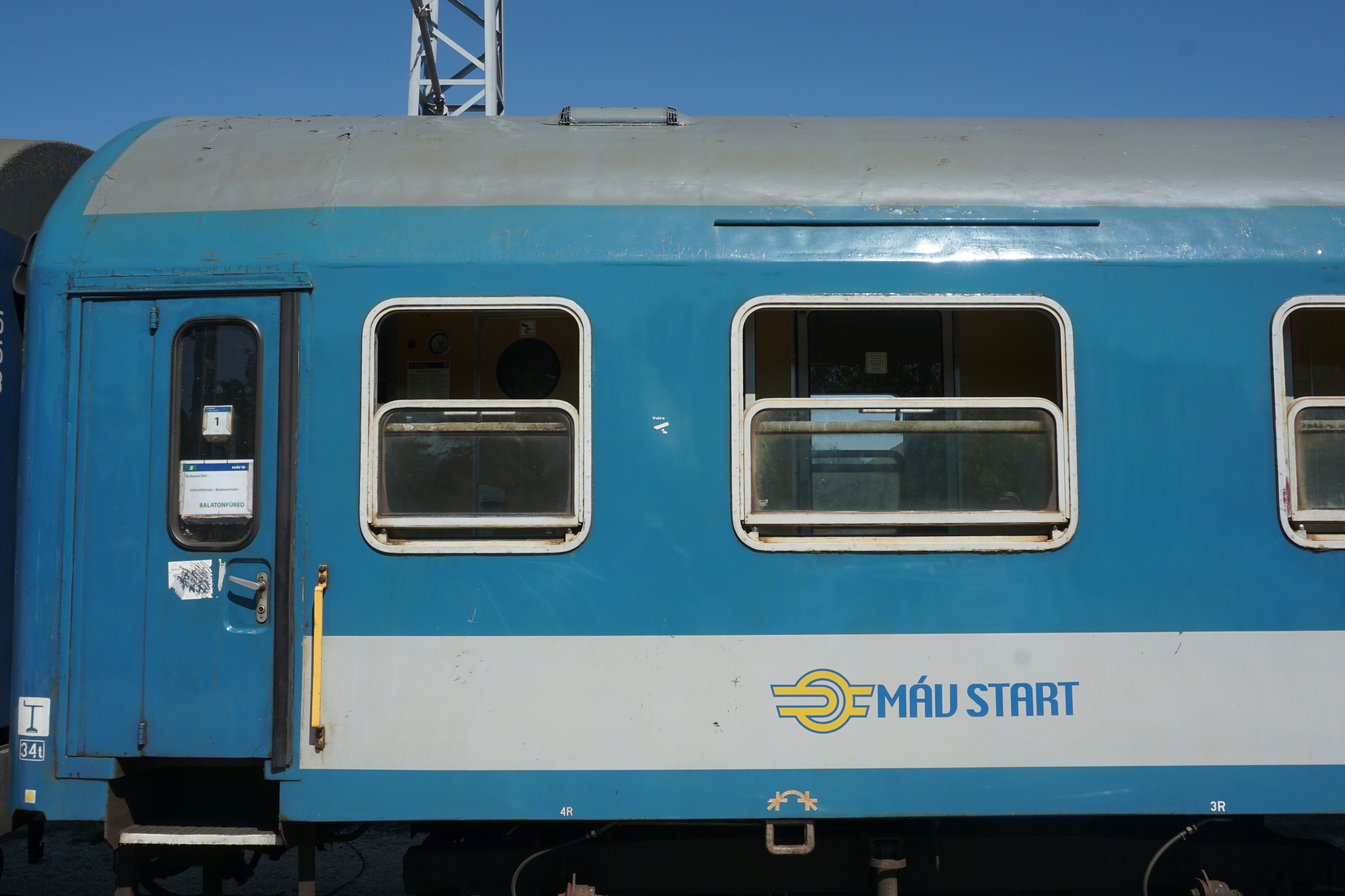 Blue Railcar Streaks Past a Clear Sky