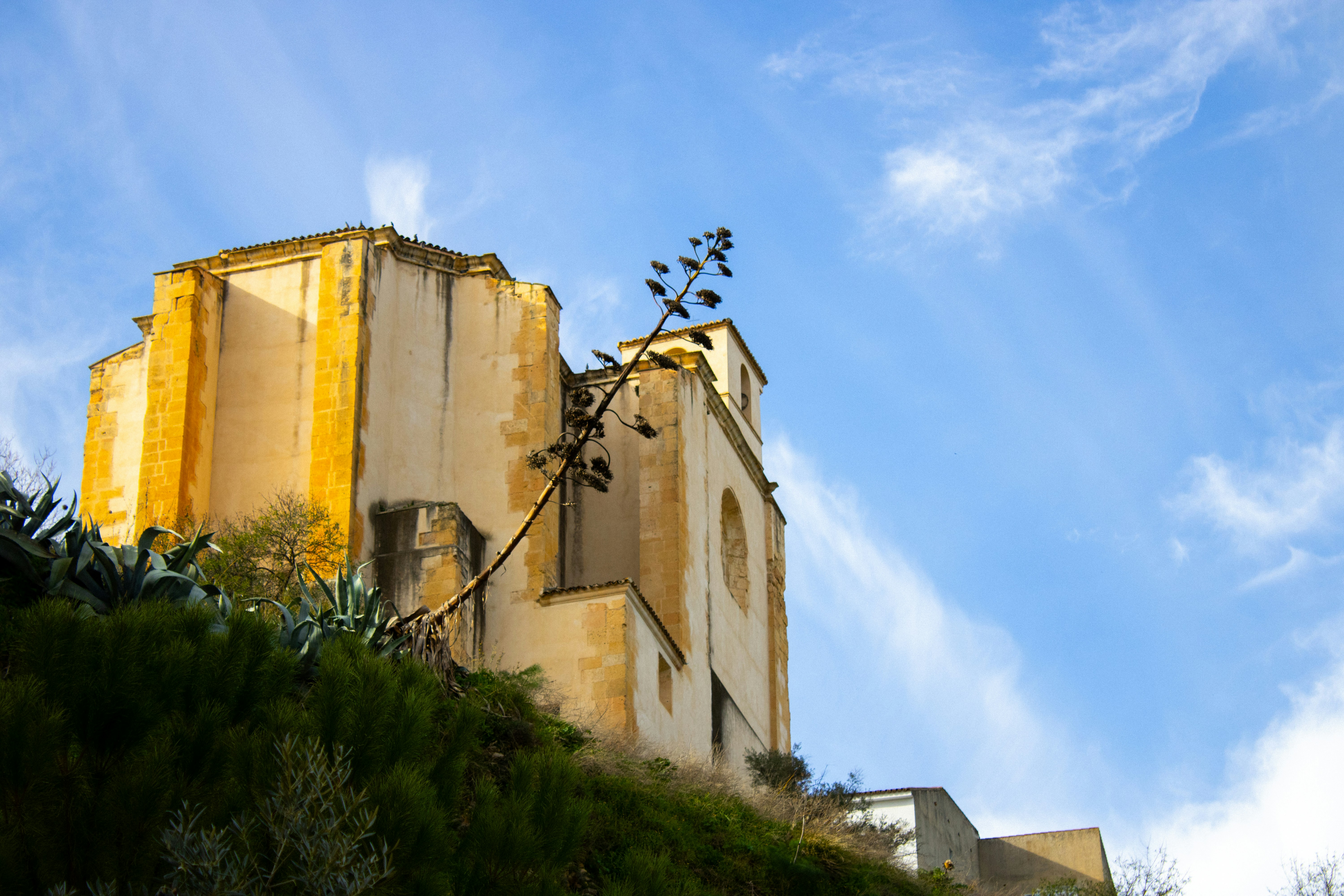 Sunlit ruin on a hill: a yellowed fortress against a clear blue sky