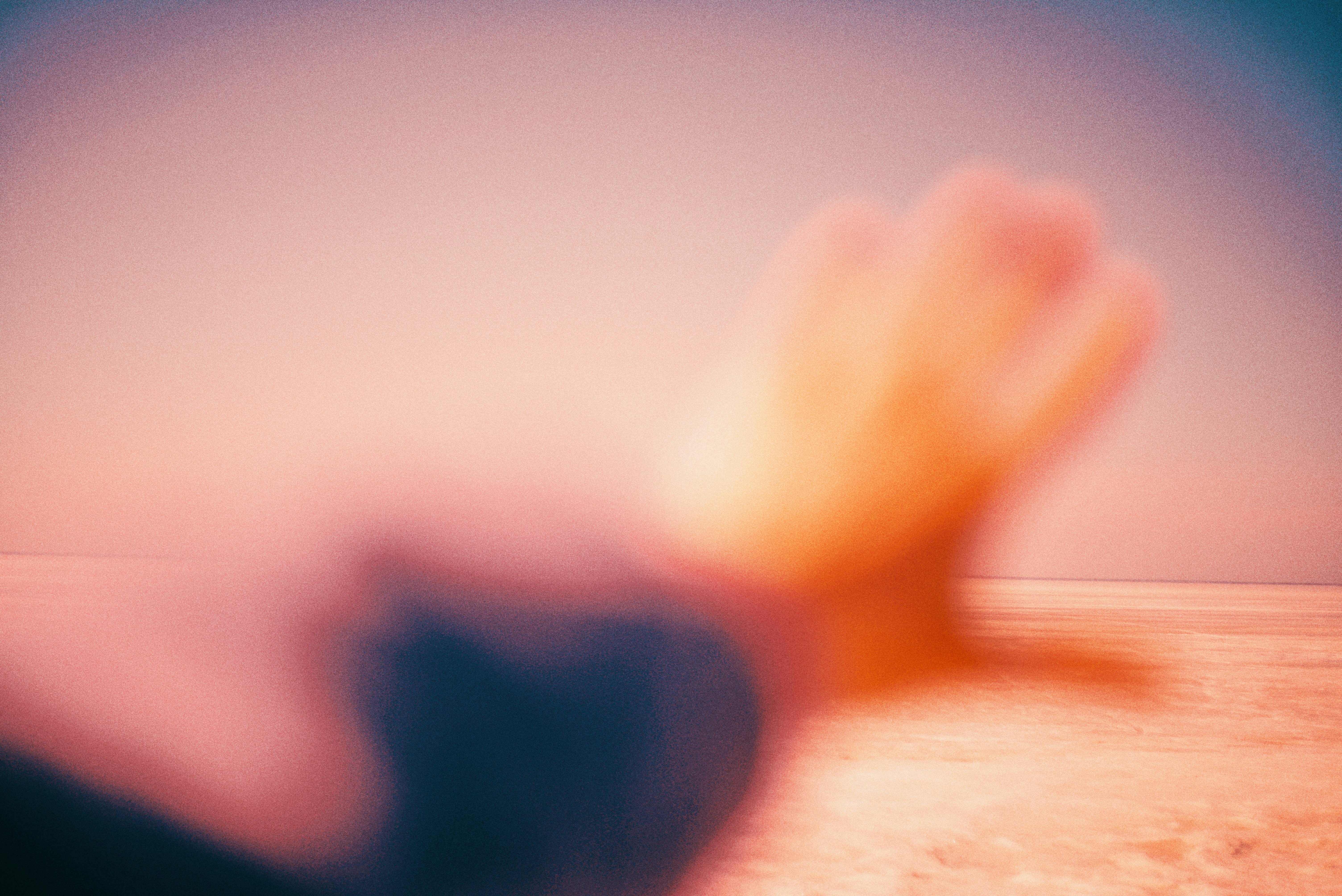 Blurred Horizon: A Soft Glimpse of Warm Light and Hand in Motion