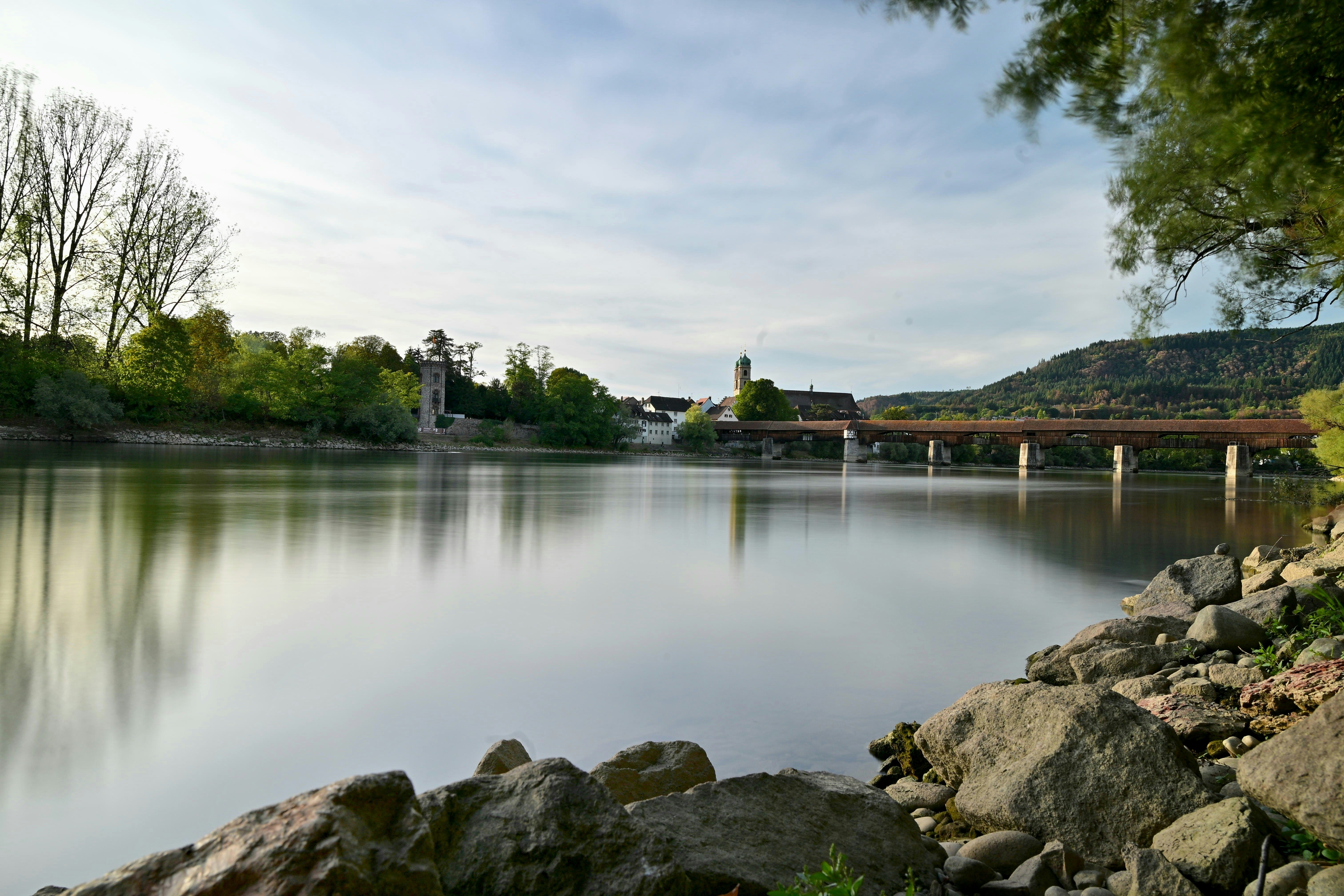 Calm riverbank with distant town and arched bridge