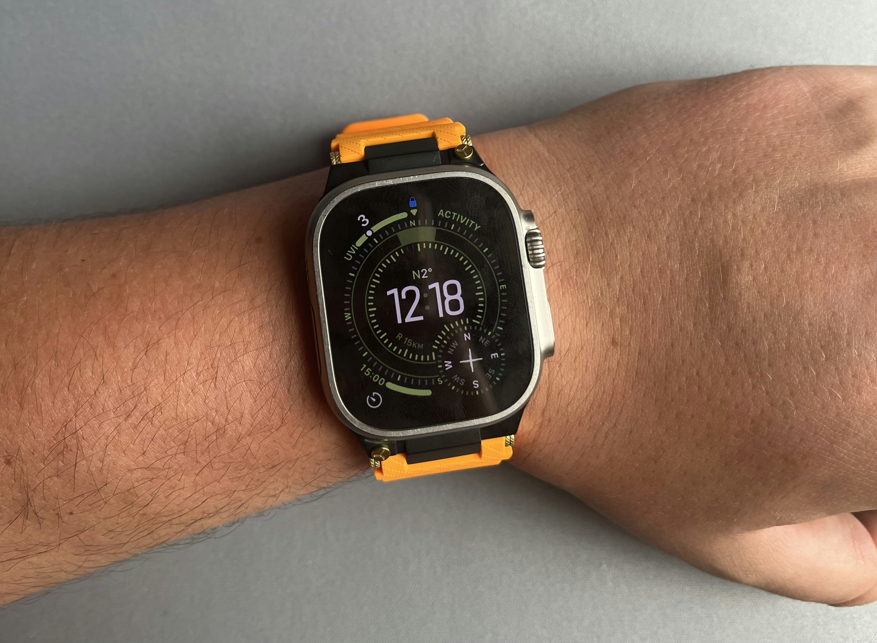 Orange-capped smartwatch on a sunlit wrist