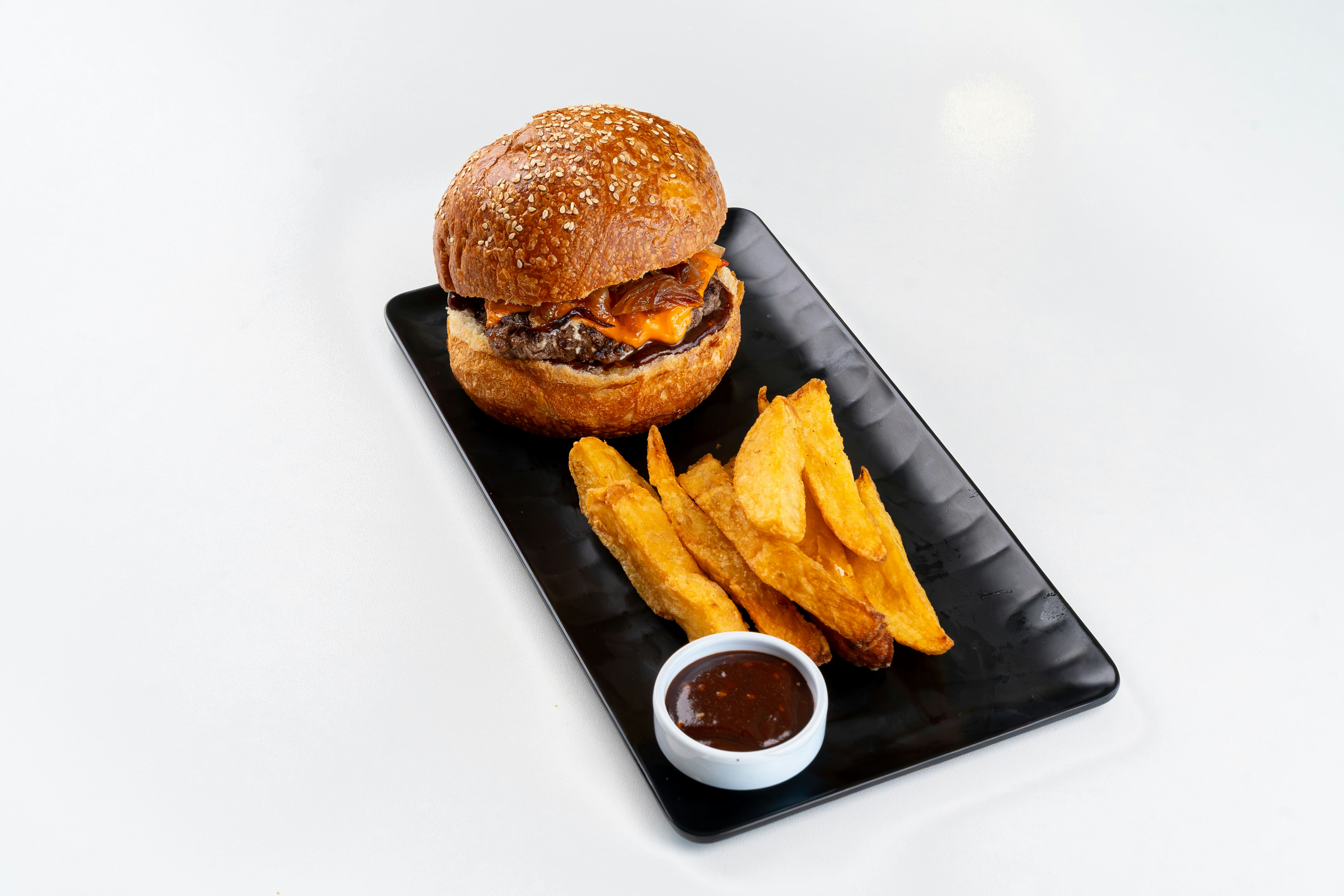 Sesame Bun Burger with Fries on a Black Platter