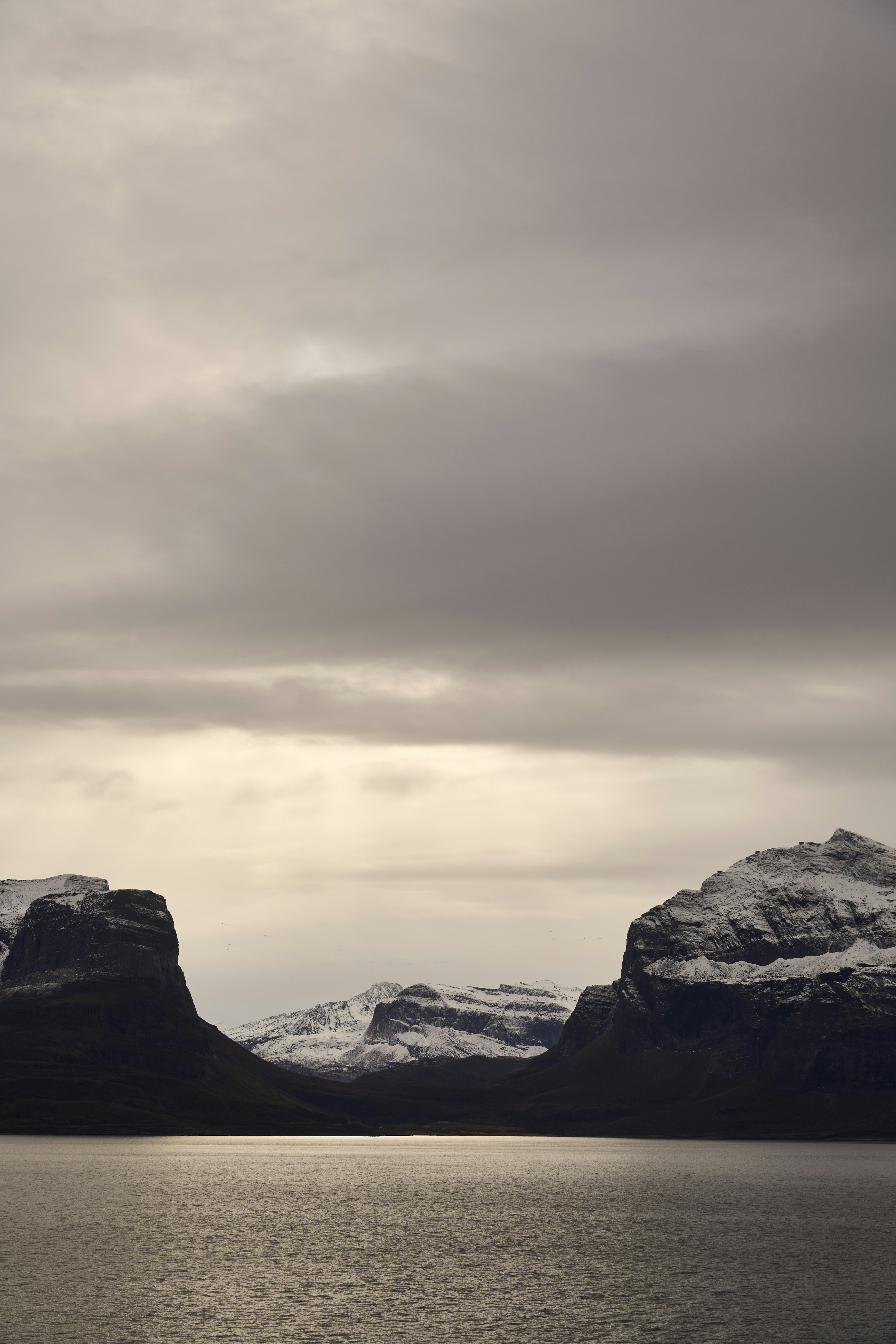 Snow-kissed Peaks across a Calm Fjord at Dusk